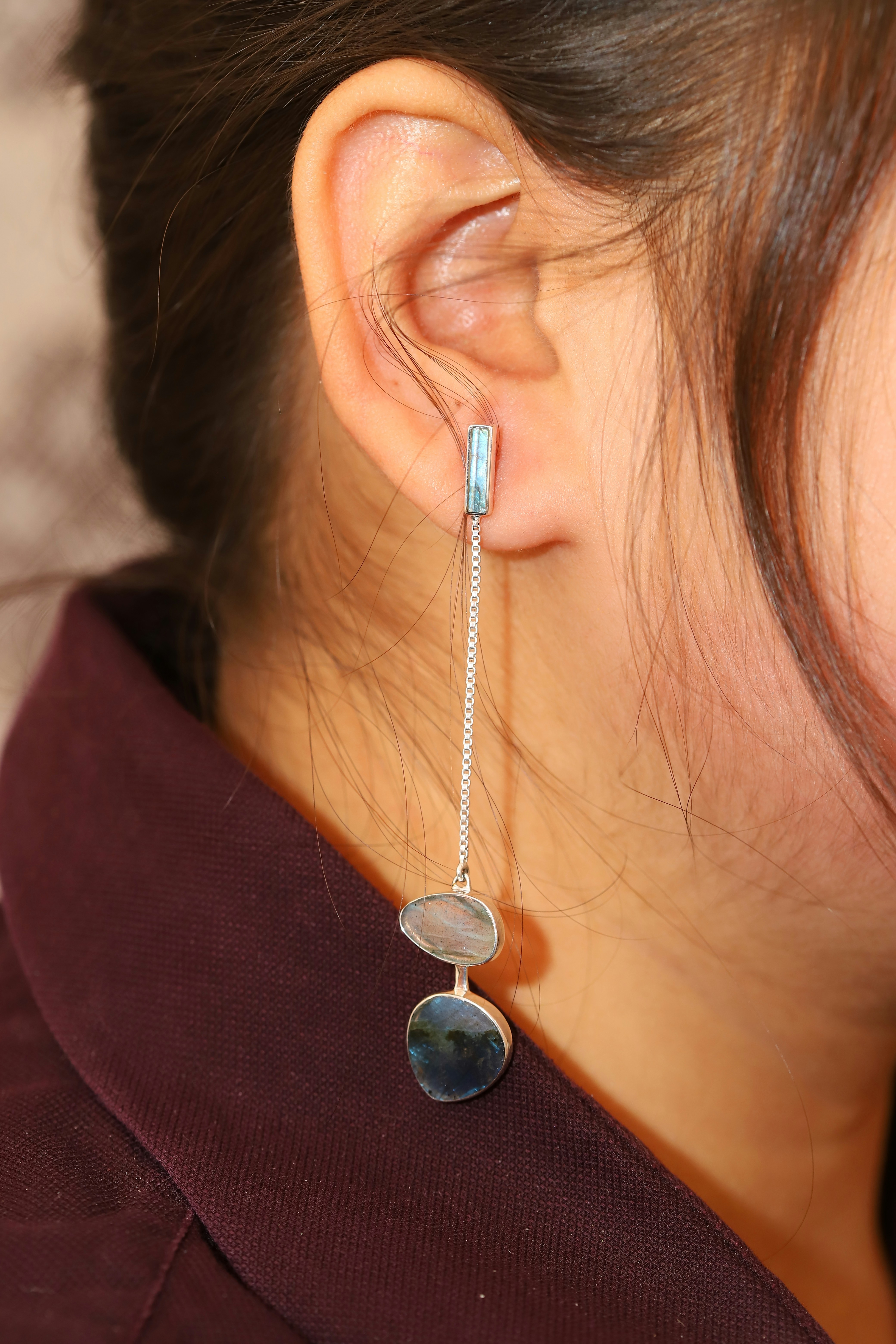 Two-Stage Silver Dangle: Close-Up of a Two-Stone Earring on Burgundy Fabric