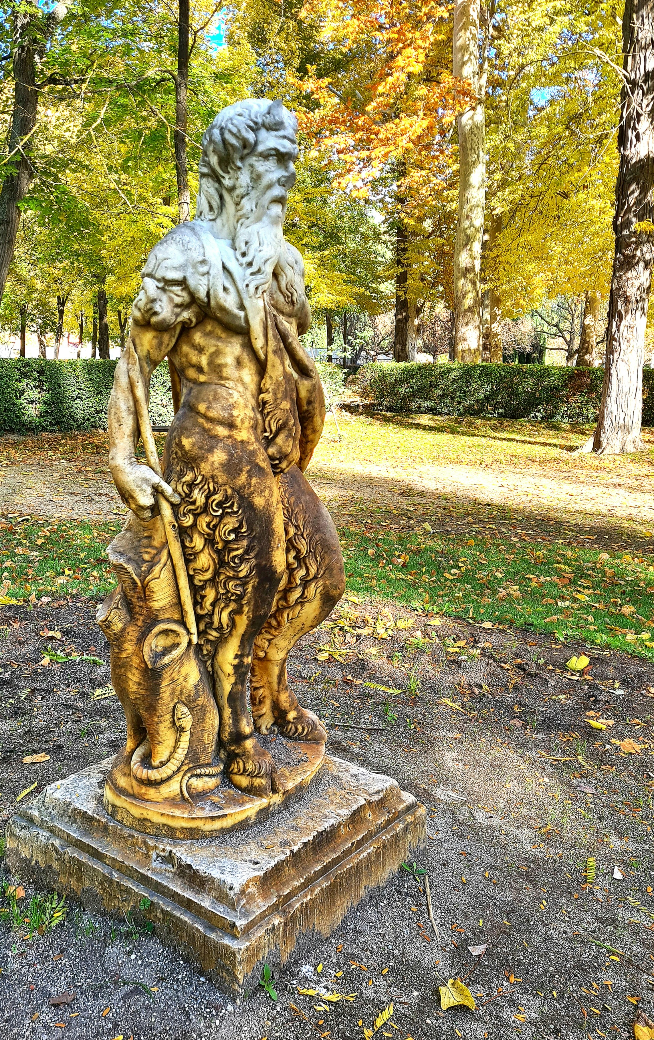 Autumn Sentinel: Weathered Statue Reaching Into Golden Park Light