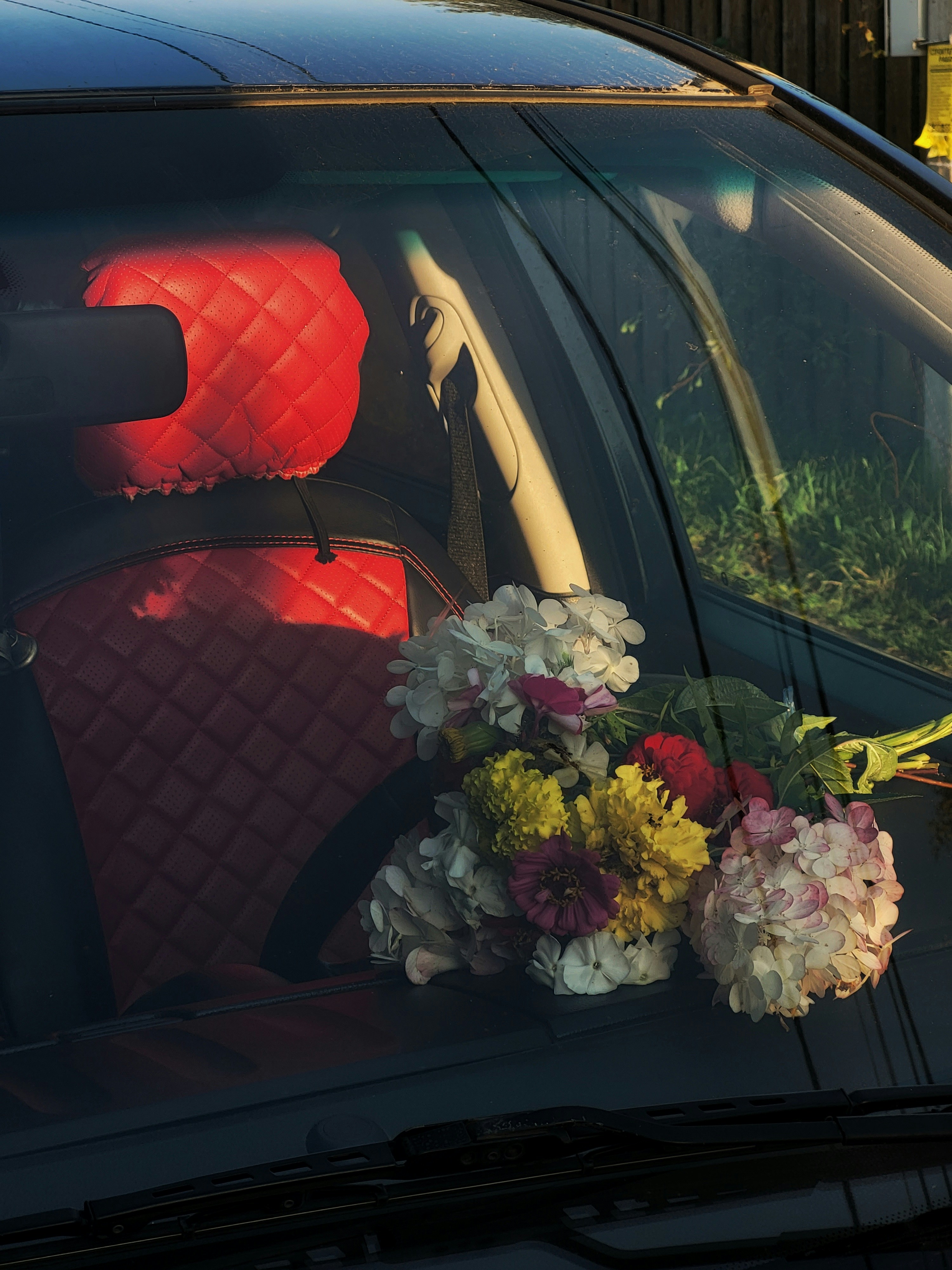 Bouquet on the Dashboard: Sunlit Interior with Red Quilted Seats