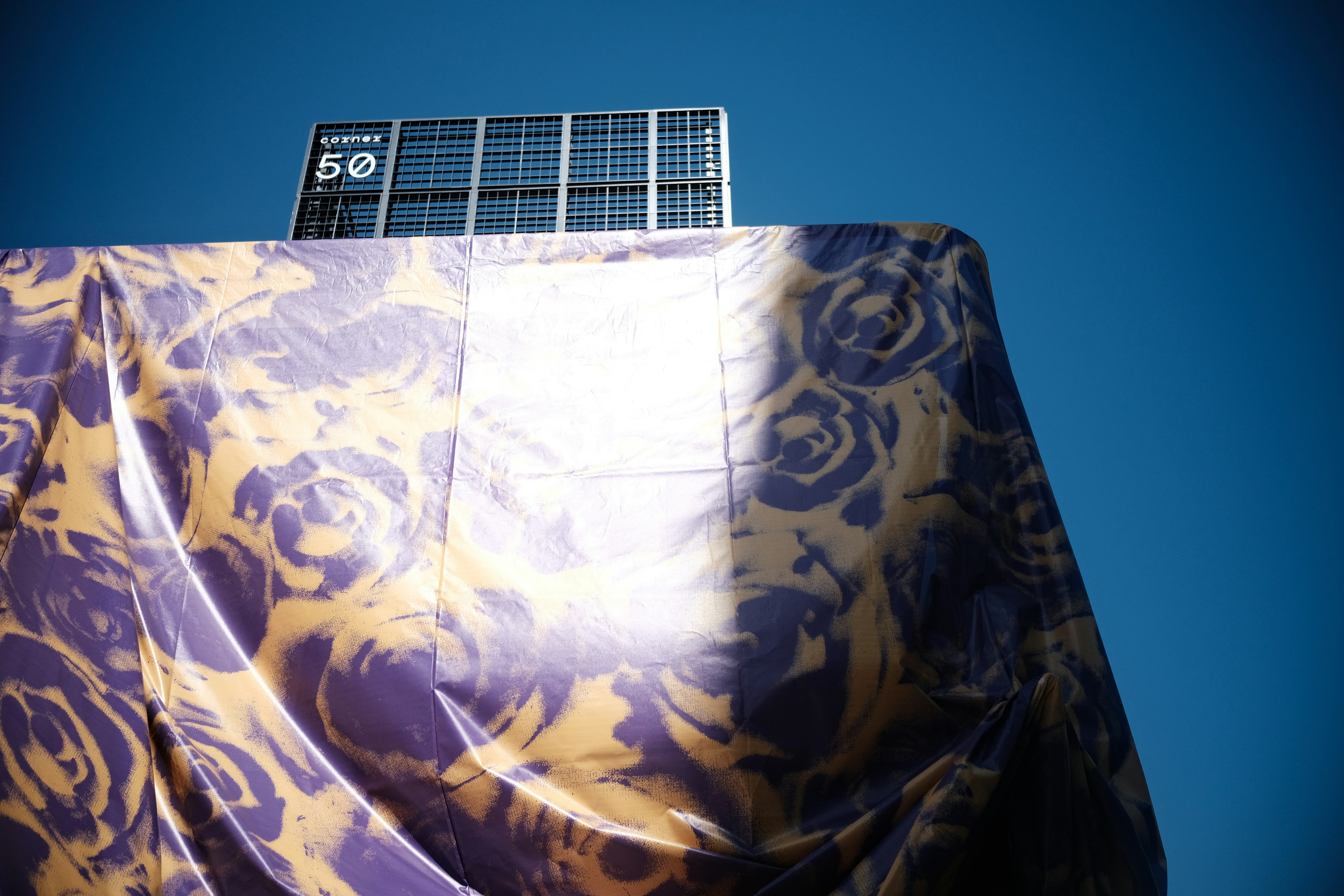 A purple and yellow cloth covering a building with a solar panel on top ...