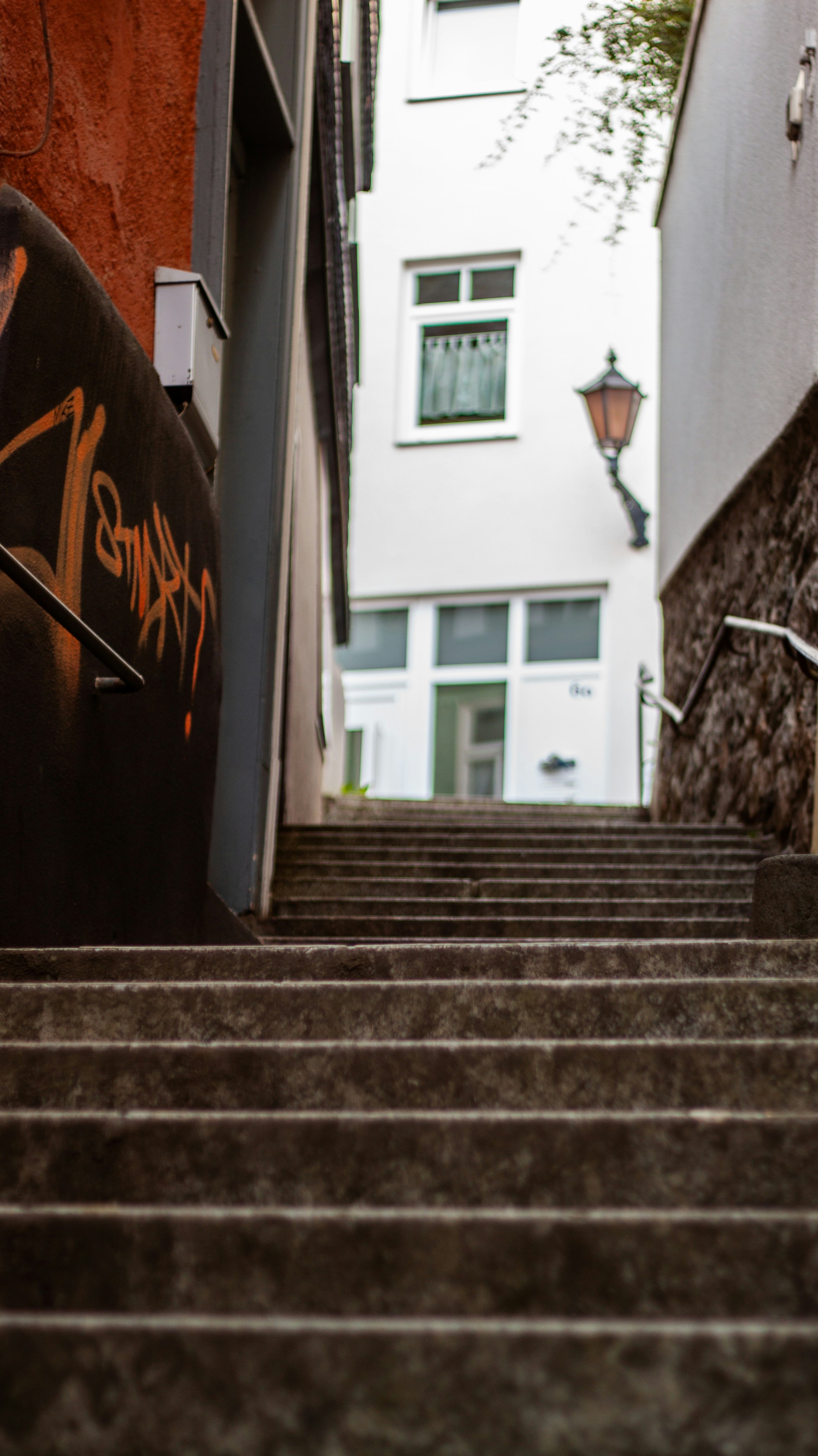 Narrow stone staircase leading up between buildings with a vintage street lamp in view.