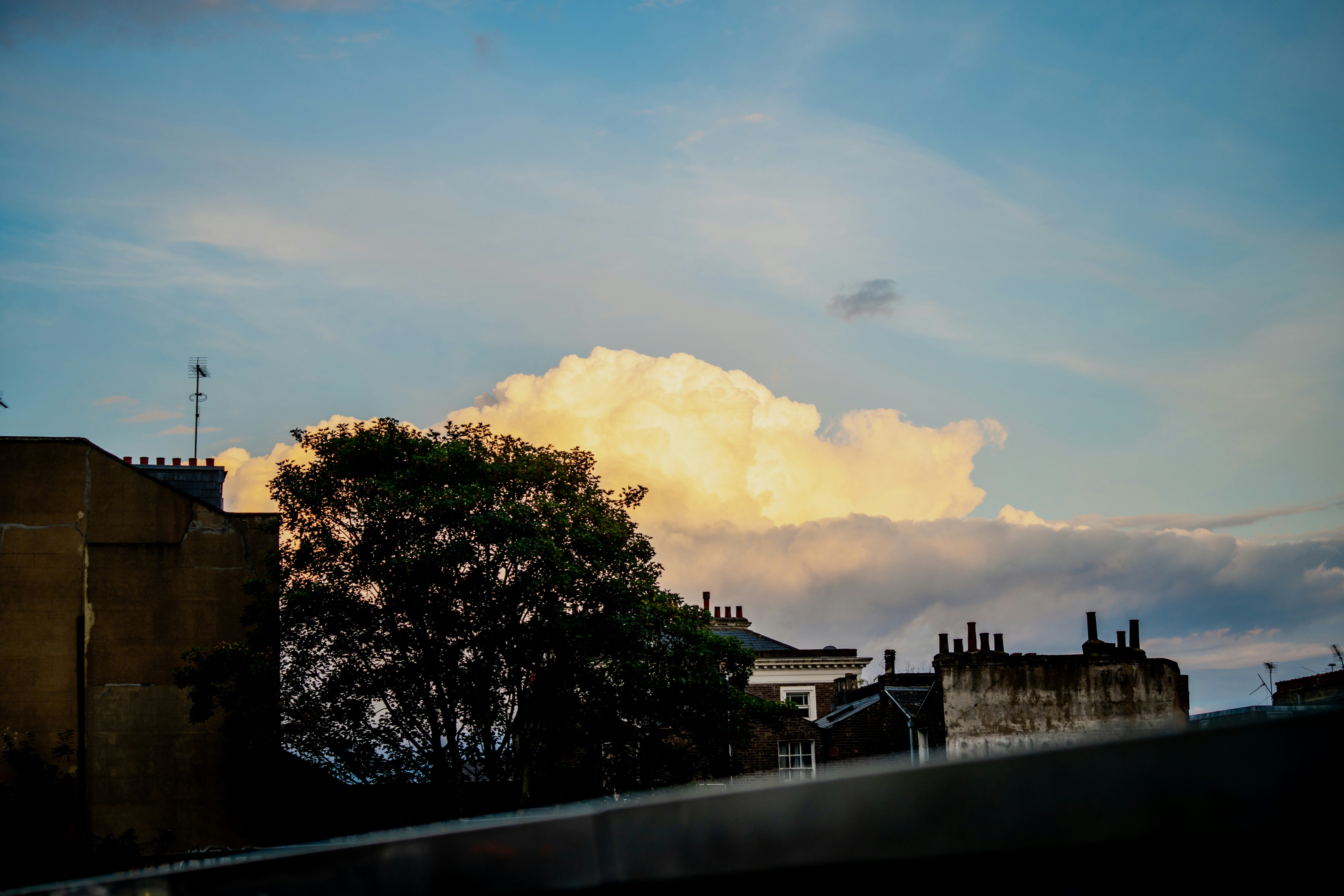 Sunlit Cumulus Over a Rooftop City Silhouette at Dusk