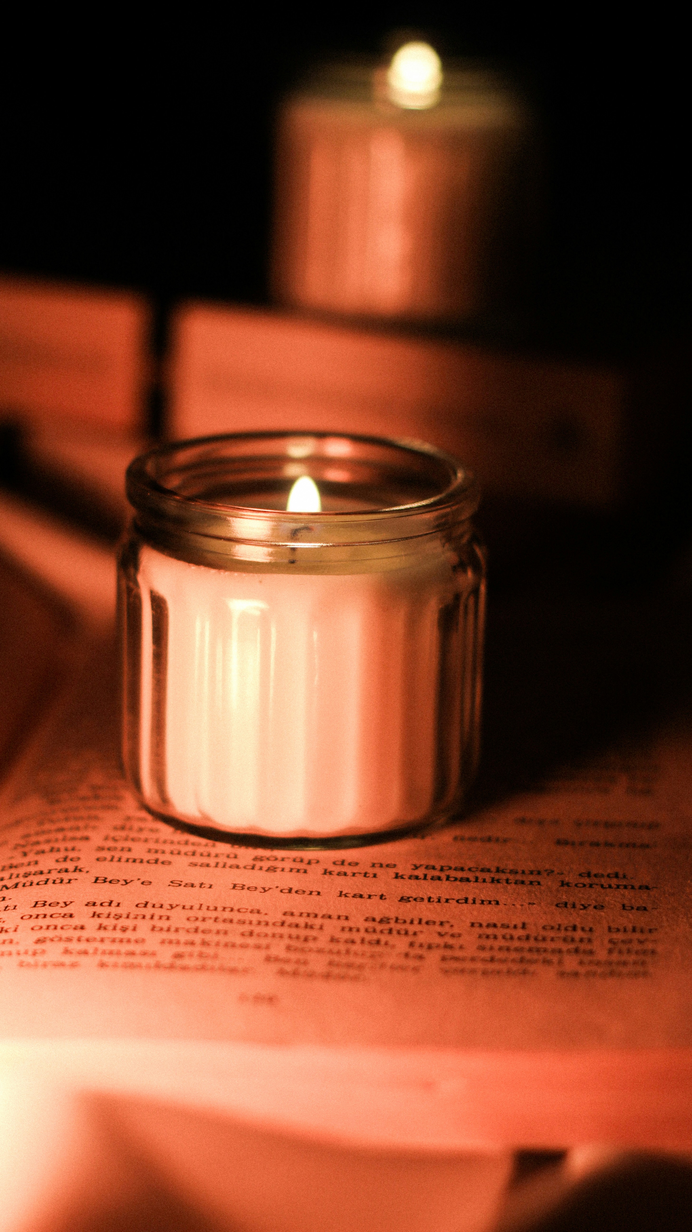Warm Glow: A lone candle in a glass jar resting on weathered pages