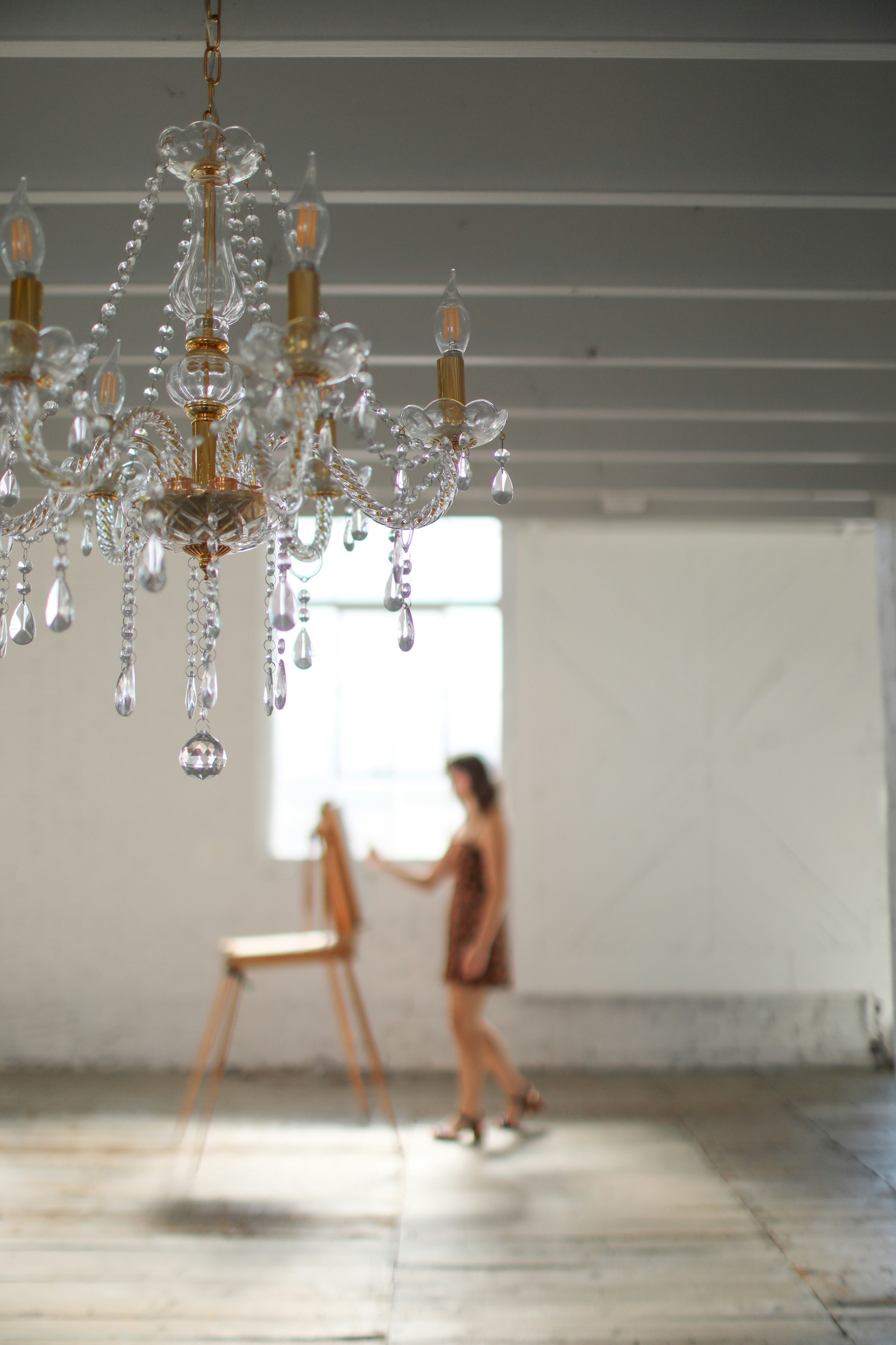 Crystal chandelier and blurred dancer: a quiet still-life within a sunlit studio