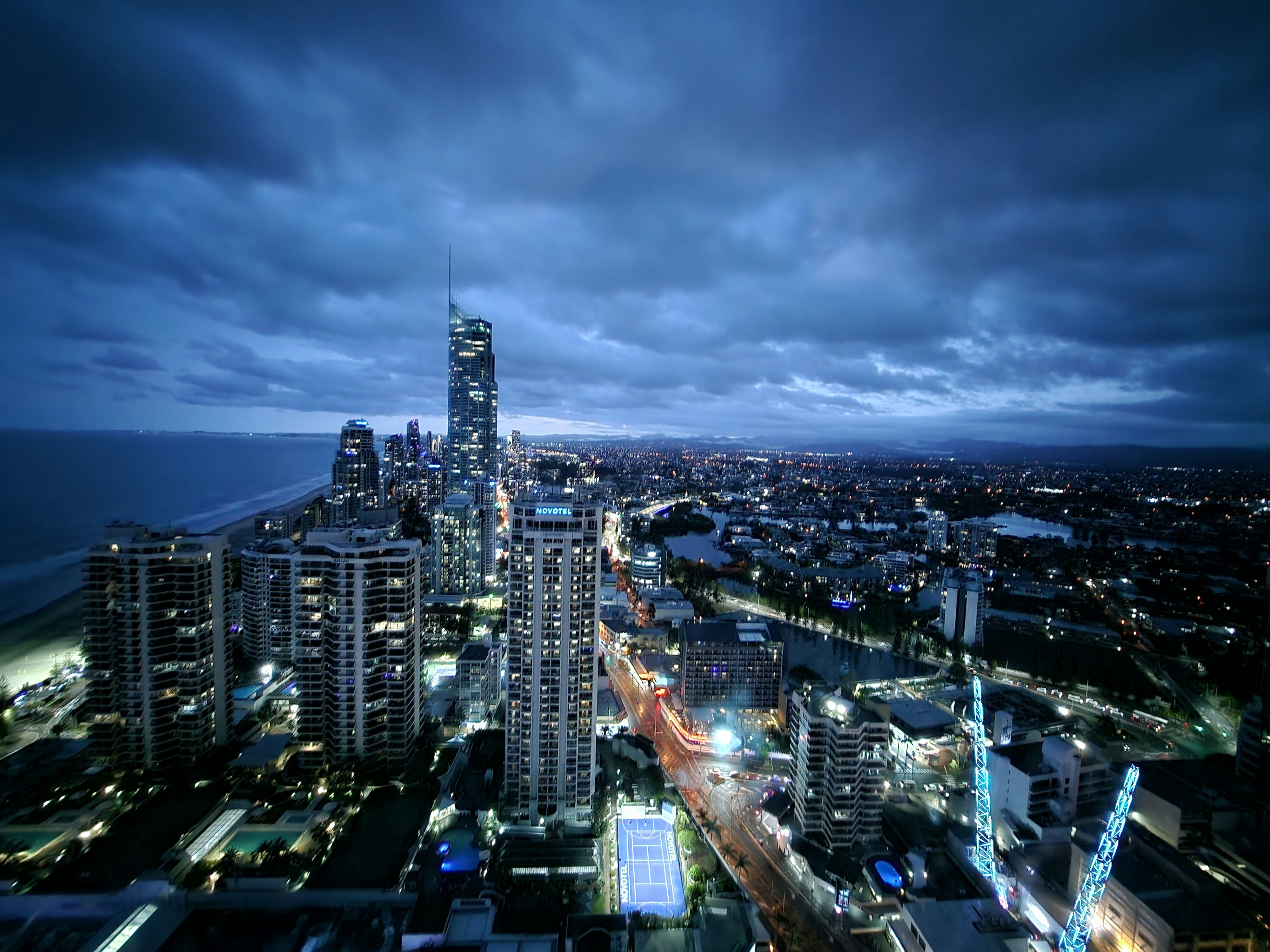 Blue-hour cityscape with a dominant skyscraper, glowing streets, and a reflective waterfront.