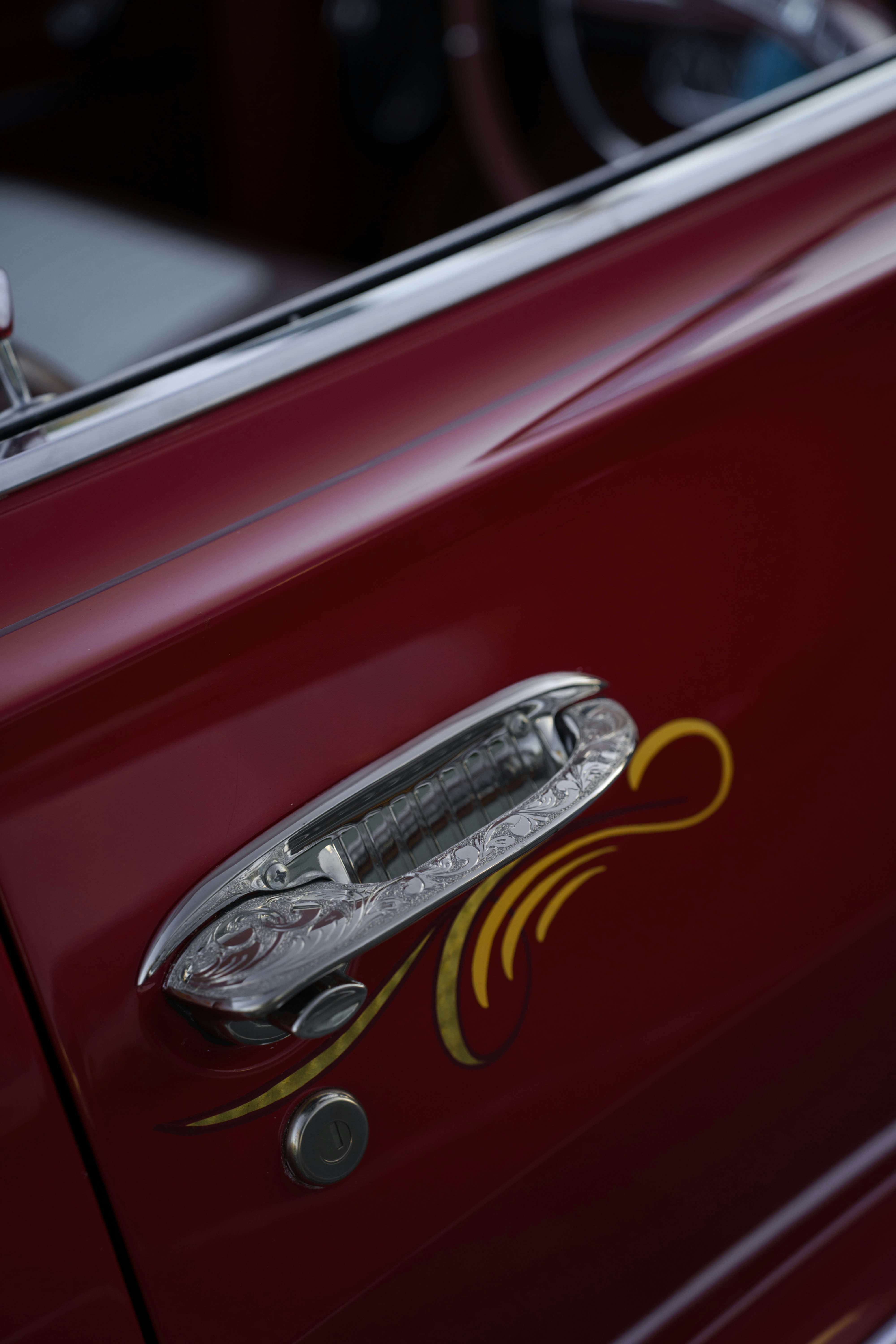 Crimson Chrome: a vintage car door handle framed by gold pinstripes