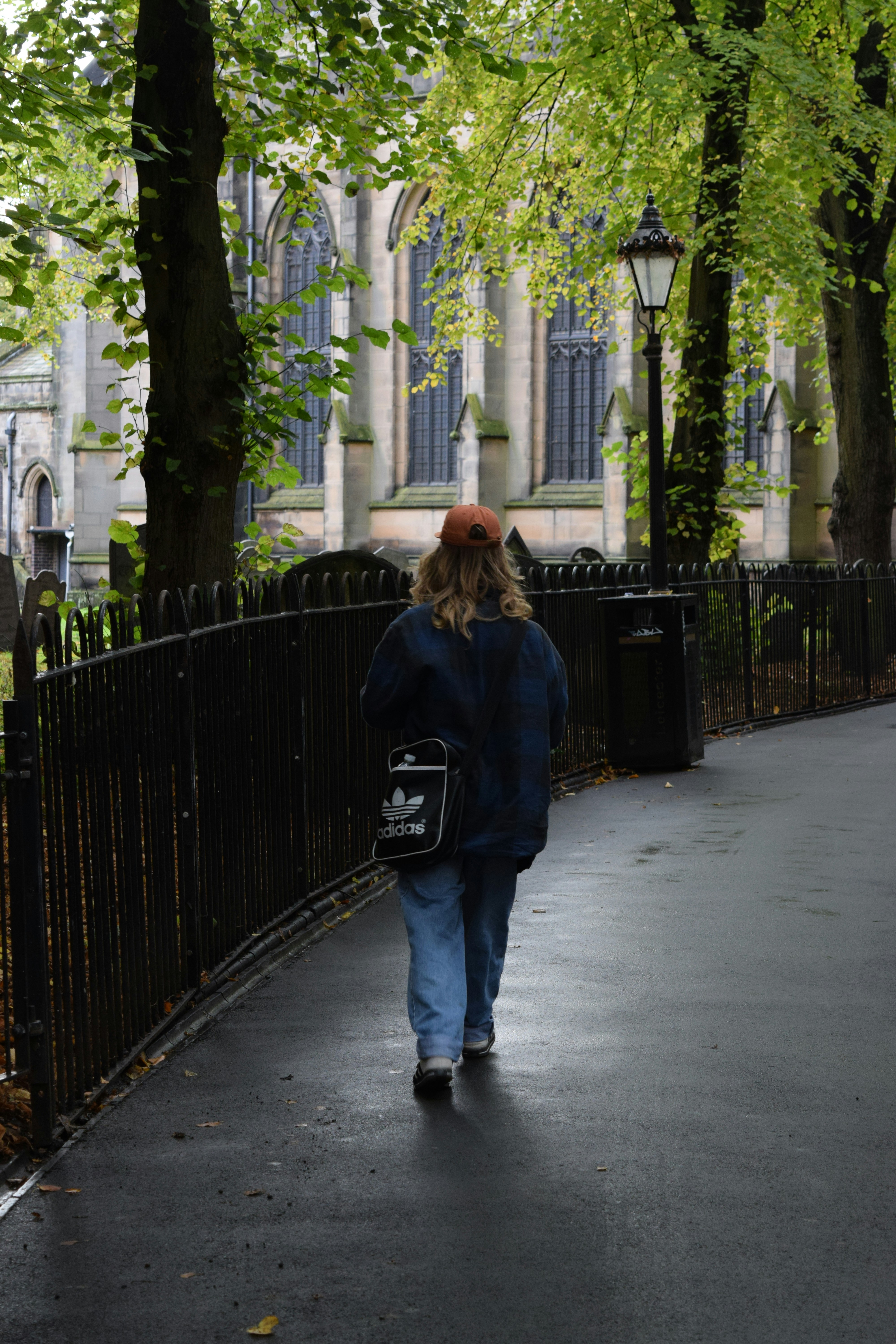 Denim, Orange Cap, and Gothic Light: A Park Walk Toward the Cathedral