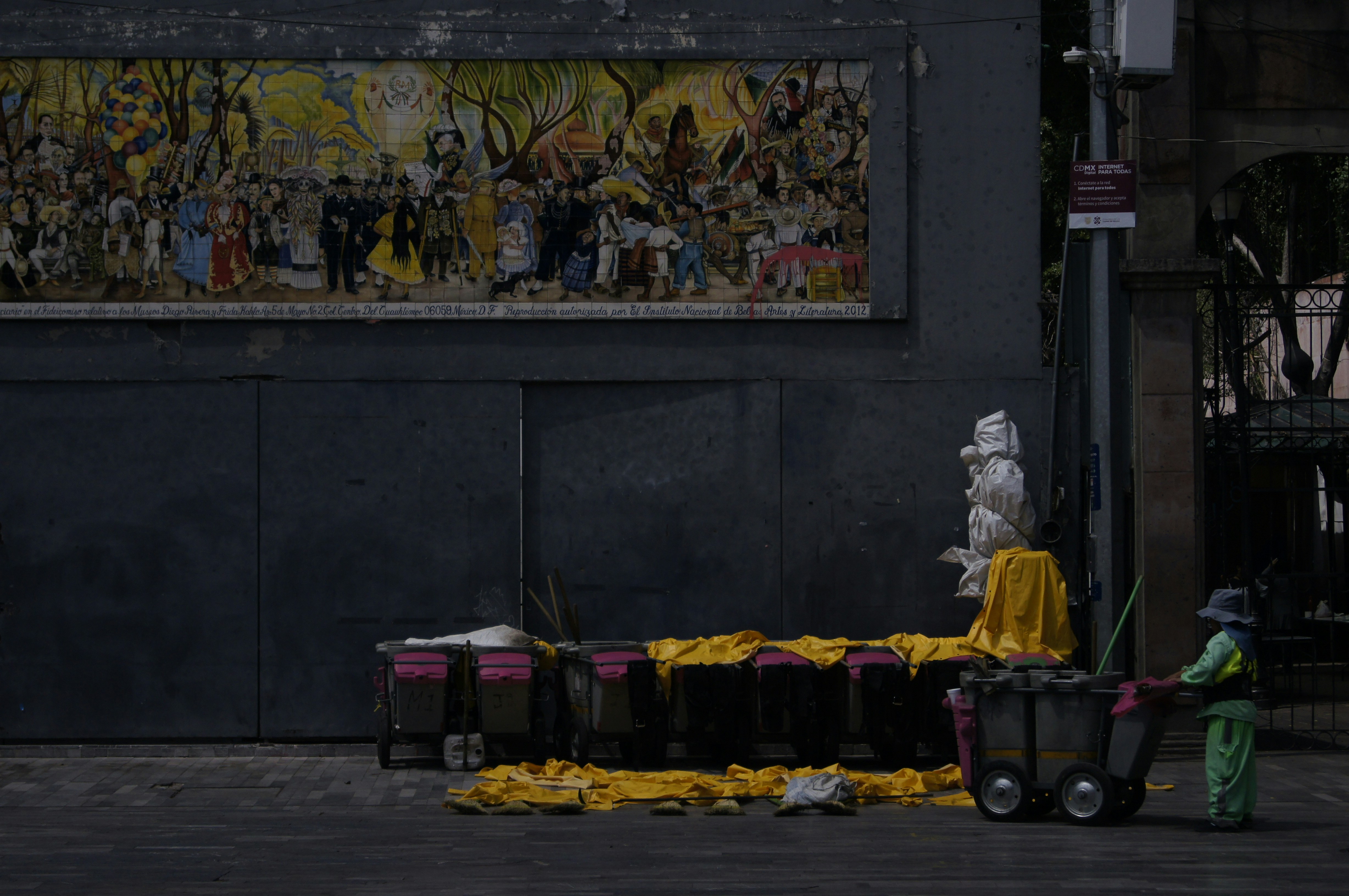 Yellow Silhouettes: A Street Vendor's Palette Beneath a City Mural