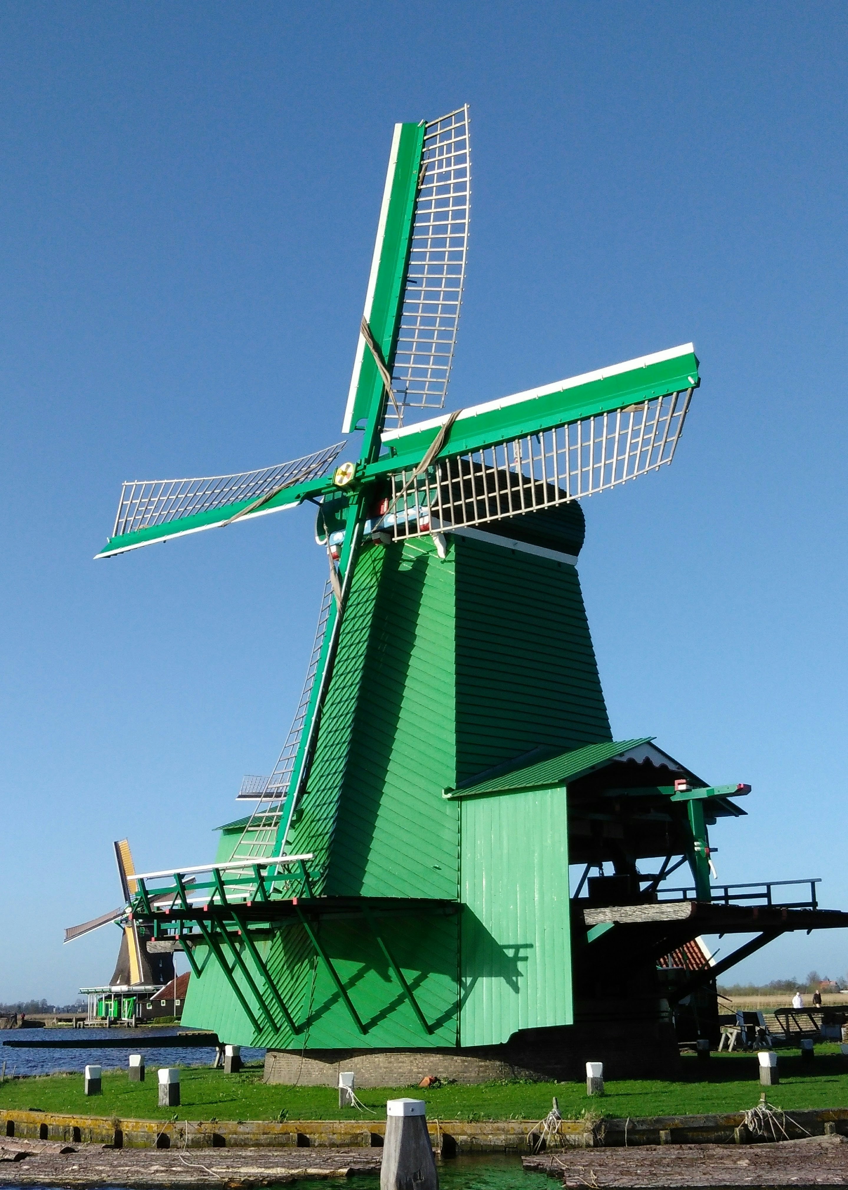 a green windmill sitting next to a body of water