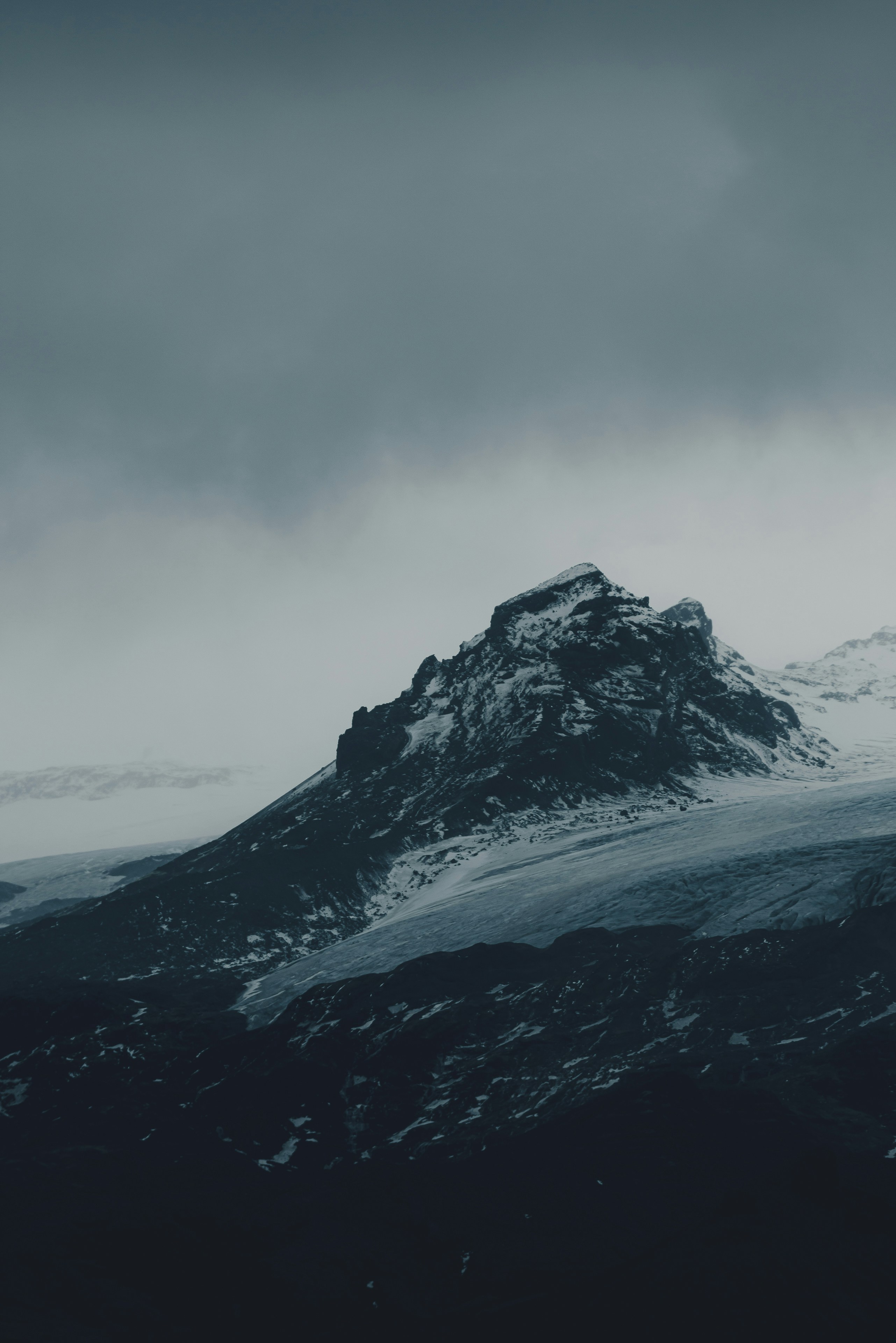 A rugged mountain peak shrouded in clouds and snow, embodying the raw beauty of nature's untouched landscapes.
