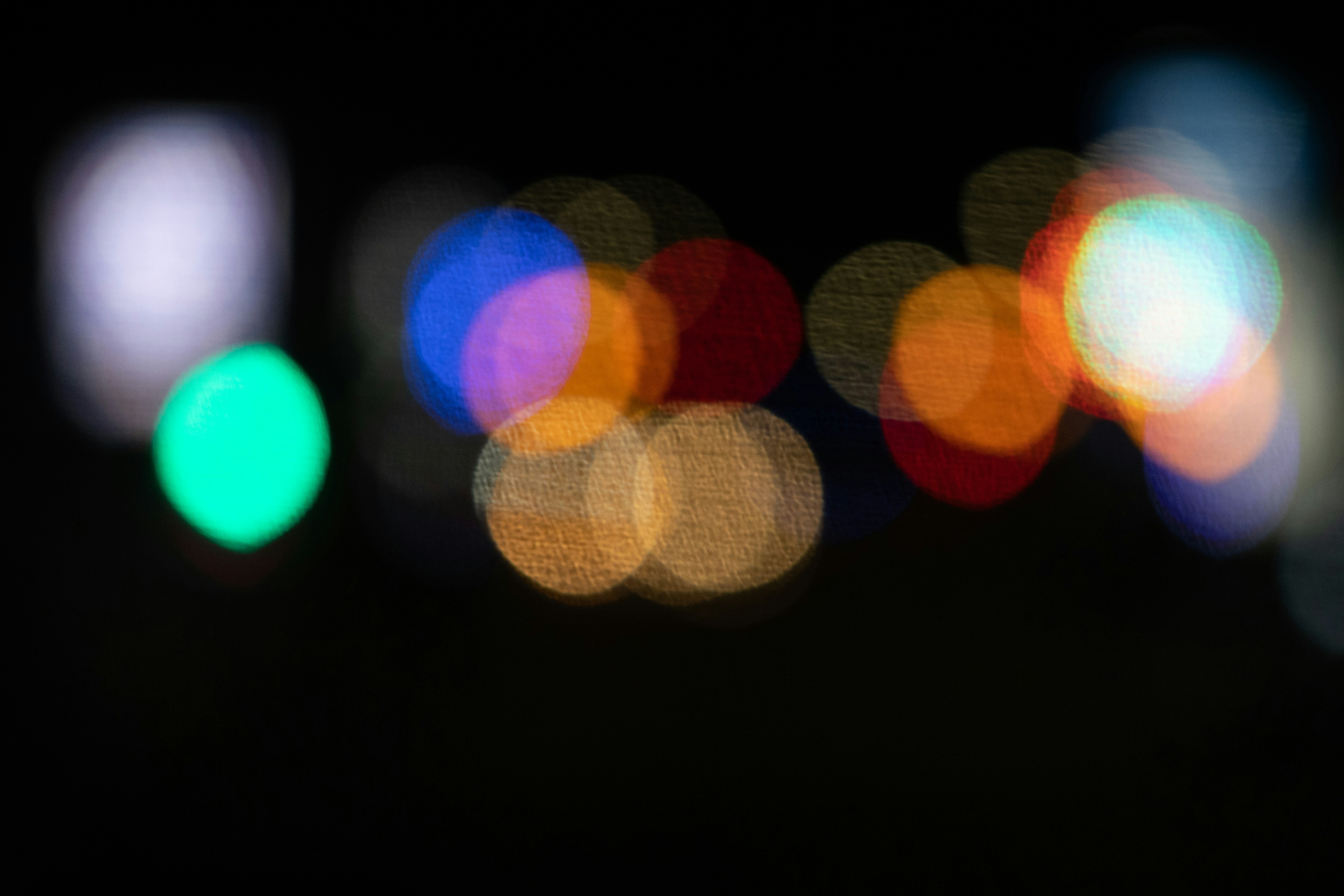 Colorful bokeh of street lights creating abstract patterns against a dark backdrop.
