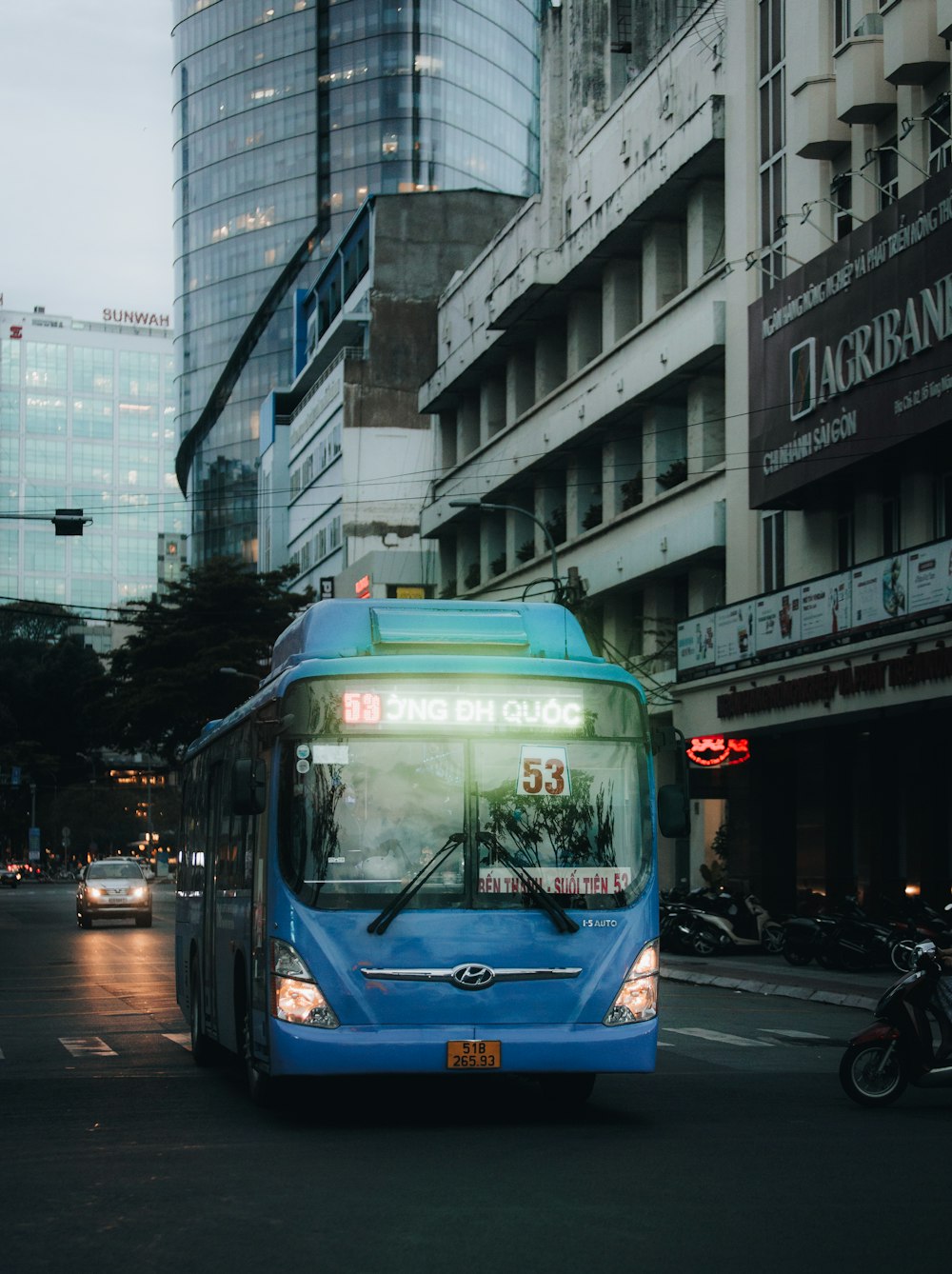 Foto Un autobús azul que circula por una calle junto a edificios altos ... Foto Un autobús azul que circula por una calle junto a edificios altos ...