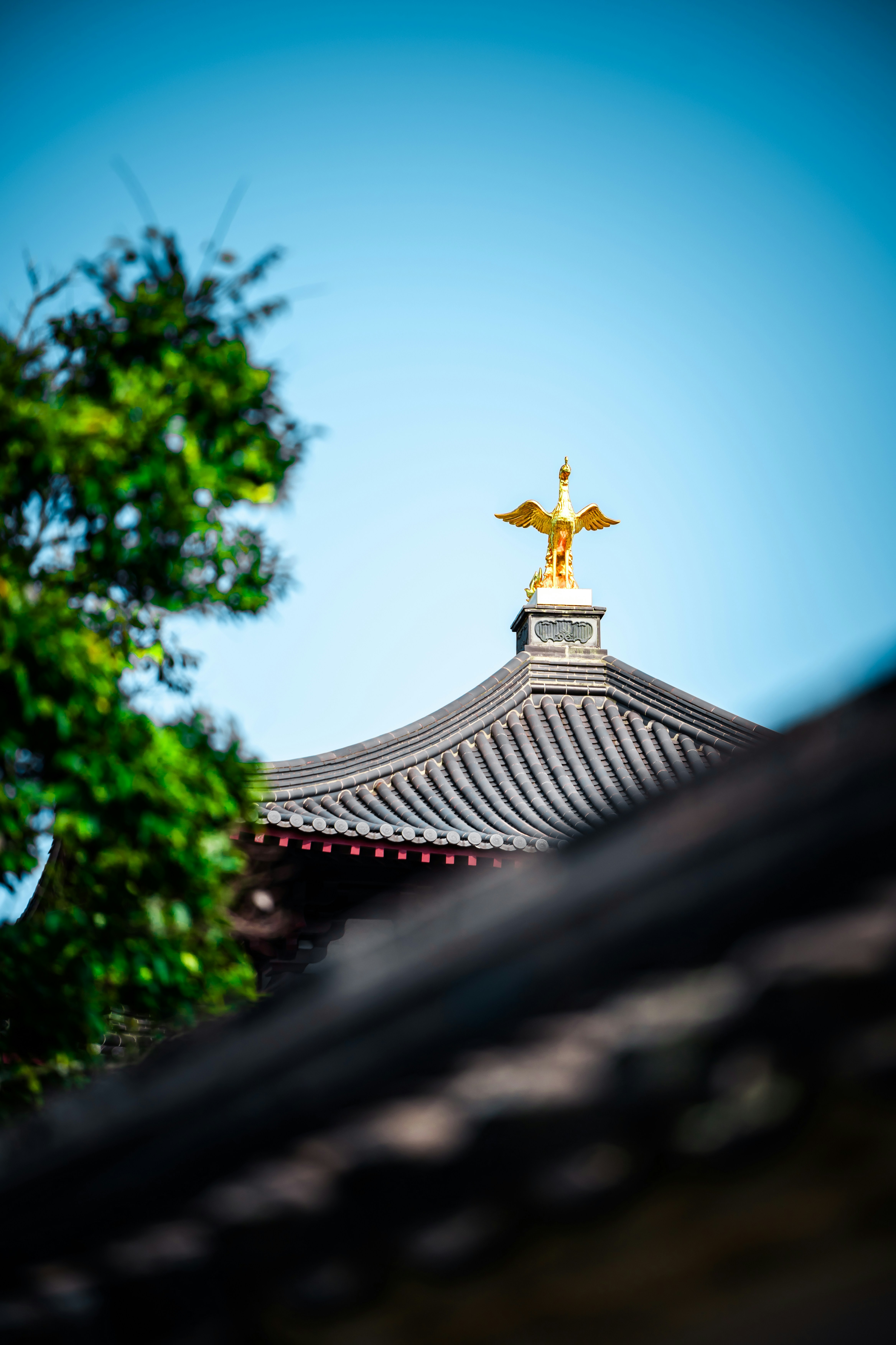 Gilded Sentinel Crowned by Cerulean Sky on a Temple Roof