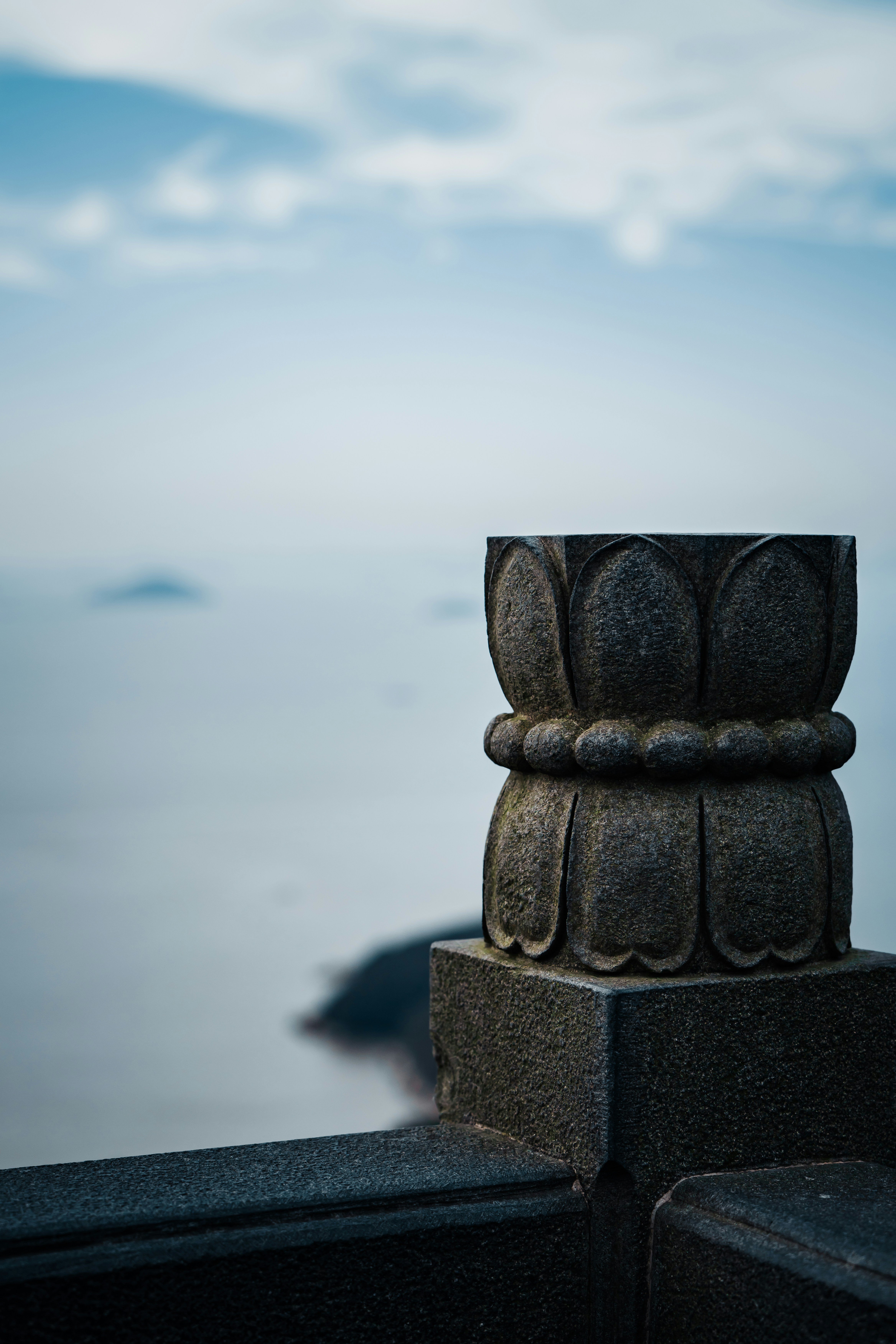 A close up of a stone pillar with a body of water in the background ...