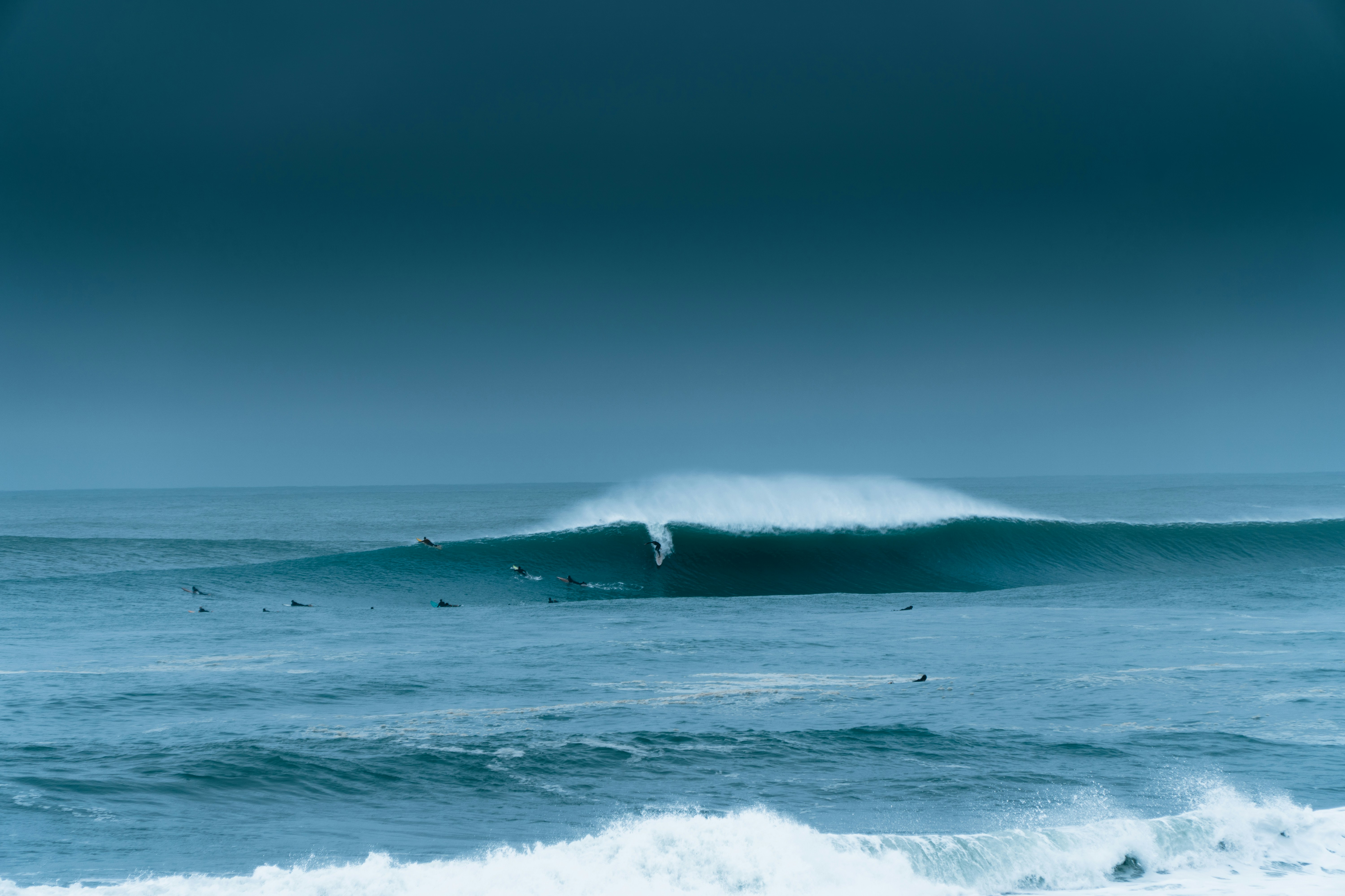 A group of surfers riding a large wave in the ocean photo – Free Sea ...