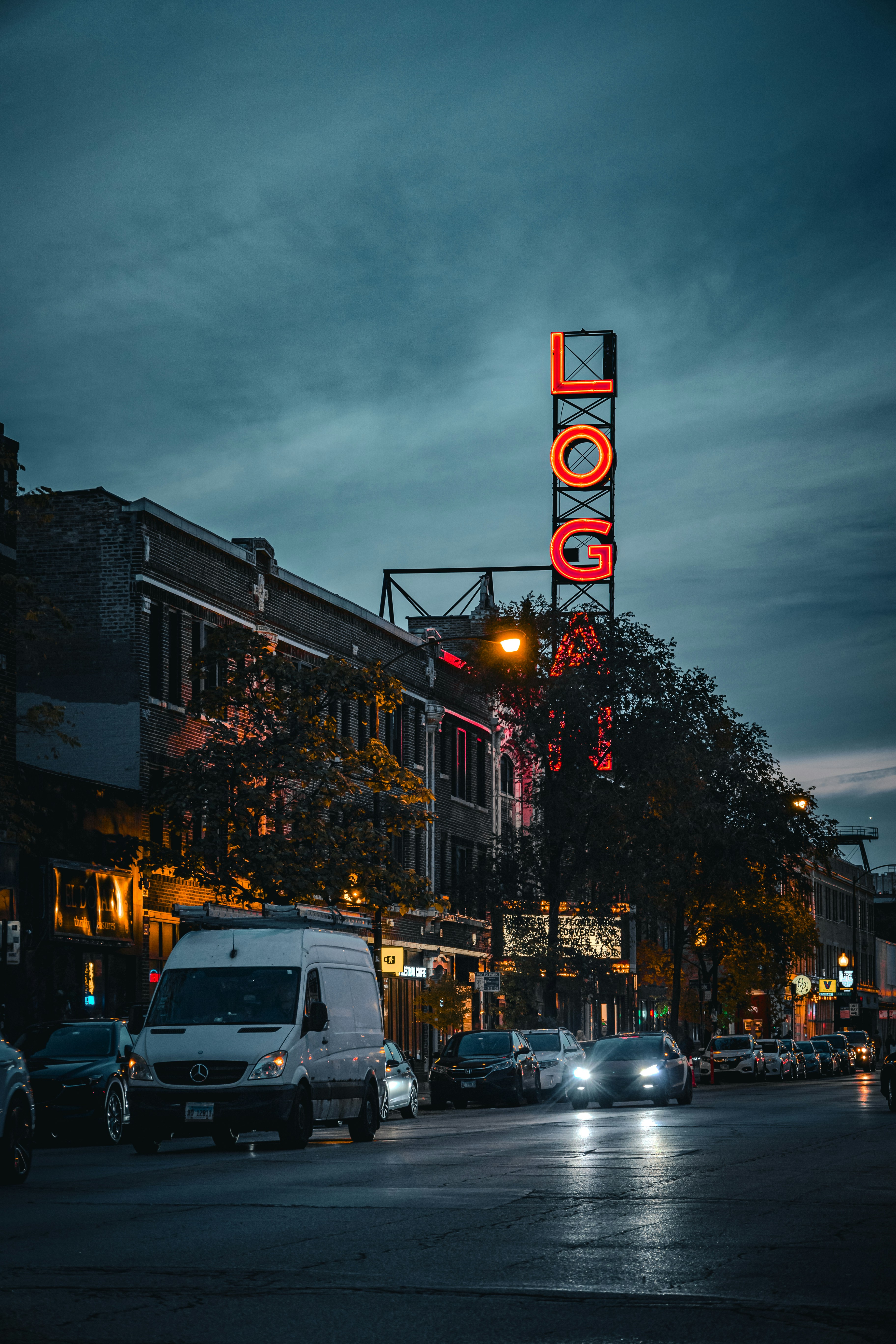 Vertical Neon Beacon: LOG Over a Rain-Washed City Street