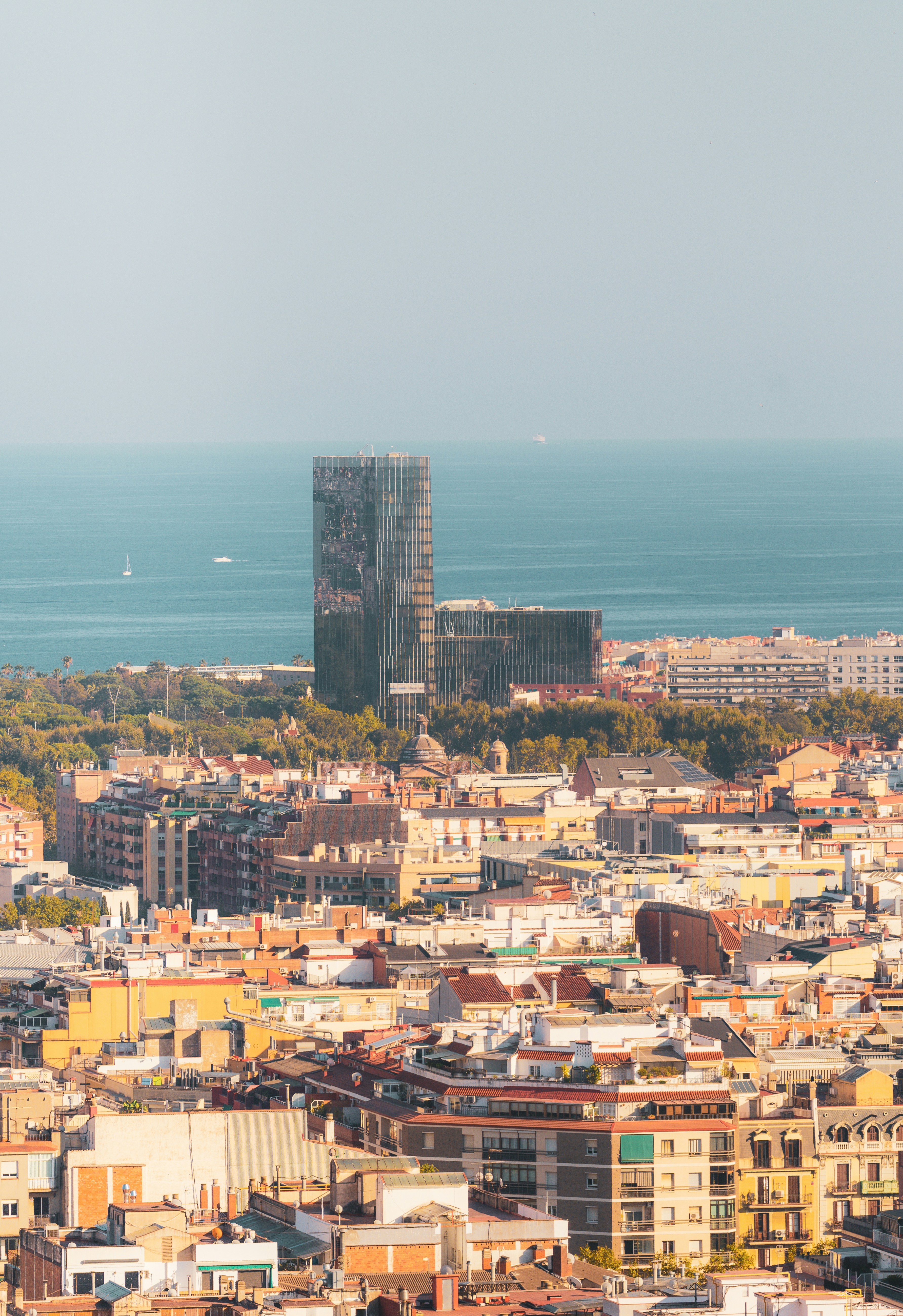 A panoramic view of a vibrant coastal city with a prominent modern building against the backdrop of the sea. The diverse architecture showcases the urban landscape's charm.