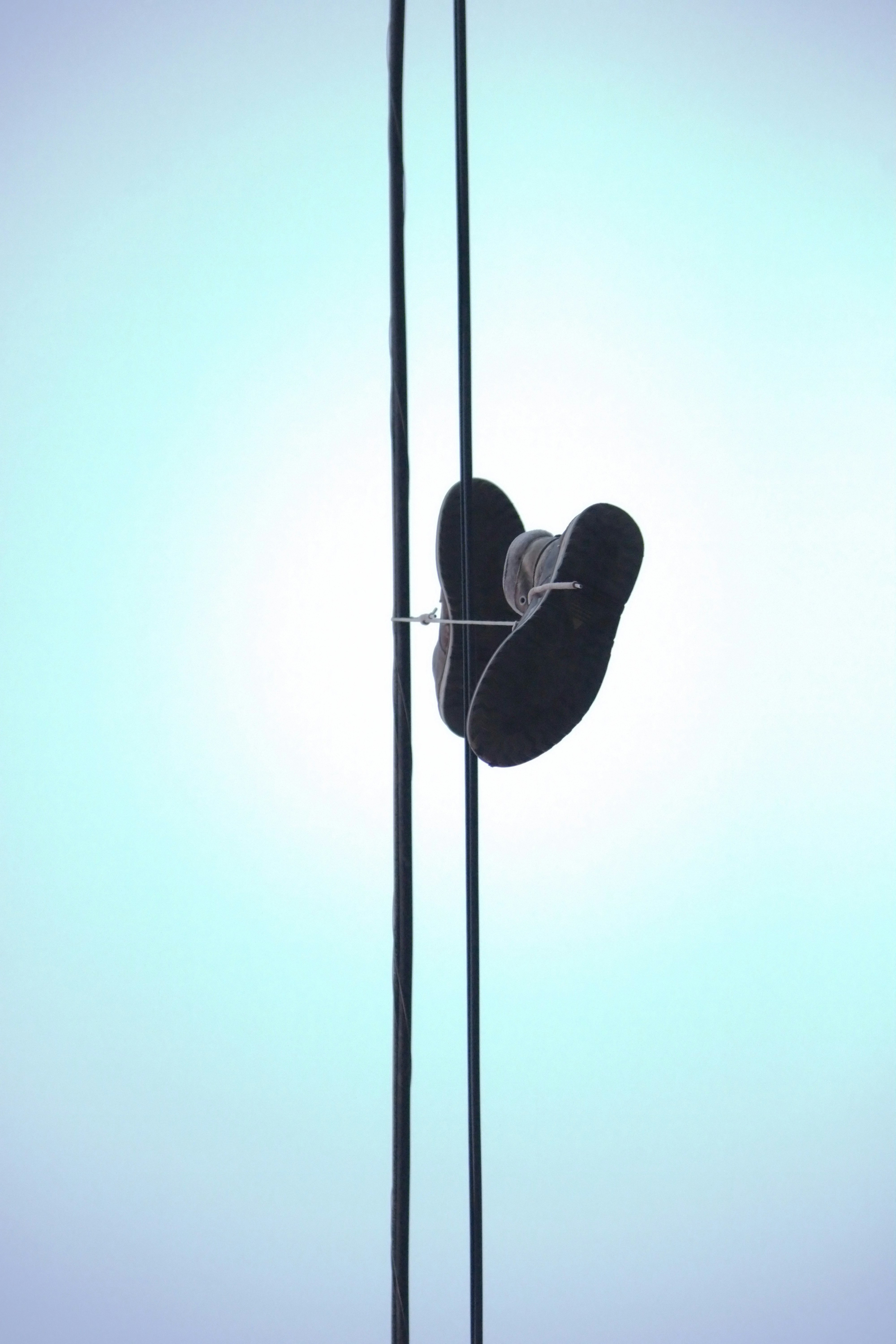 Sole on a Wire: Minimalist Shoes Against a Cerulean Sky