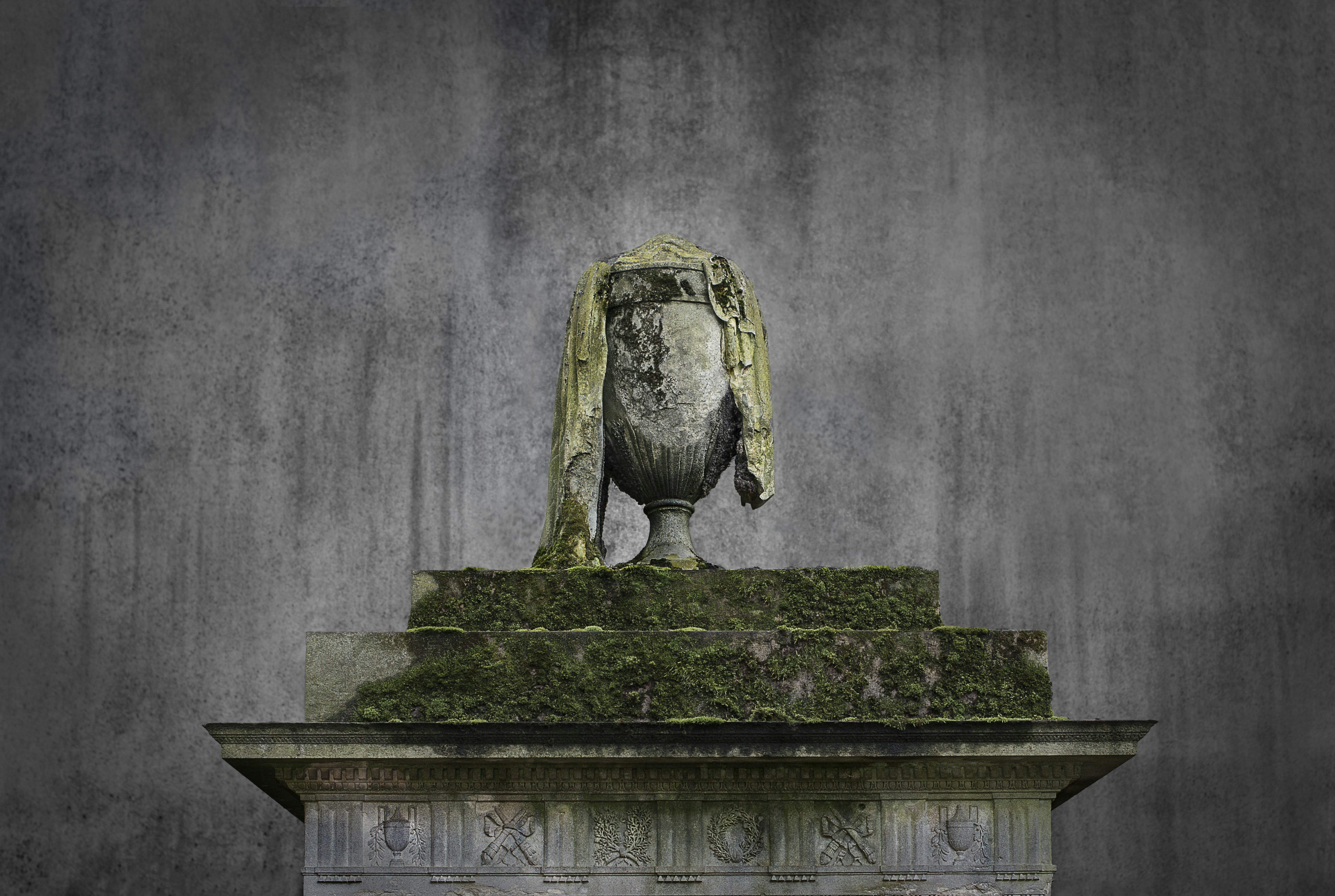 Moss-Capped Monument: A Weathered Bust Surmounts a Verdant Pedestal
