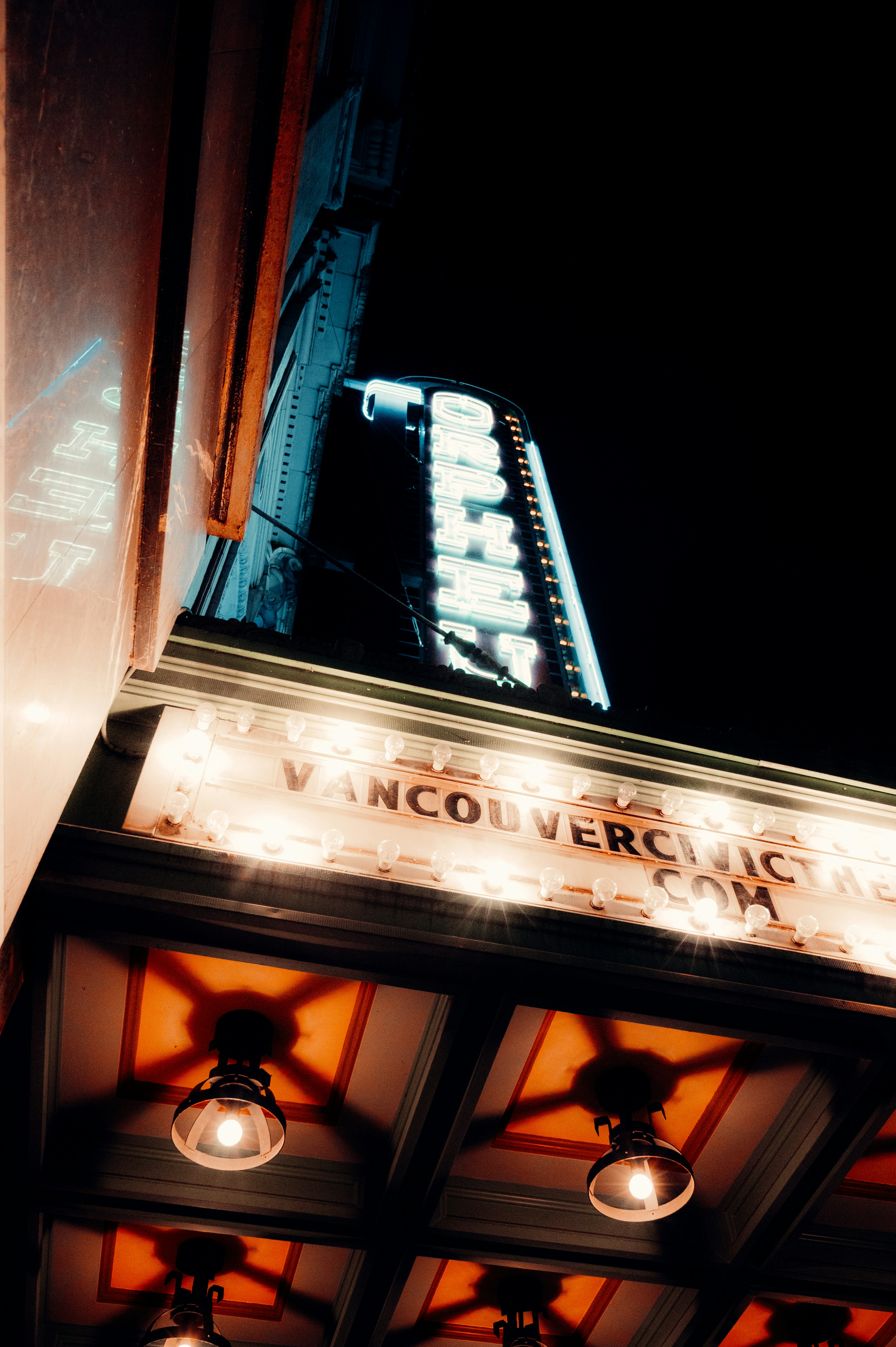 Neon Veil Over Vancouver: Night Theater Marquee and Tilted Sign