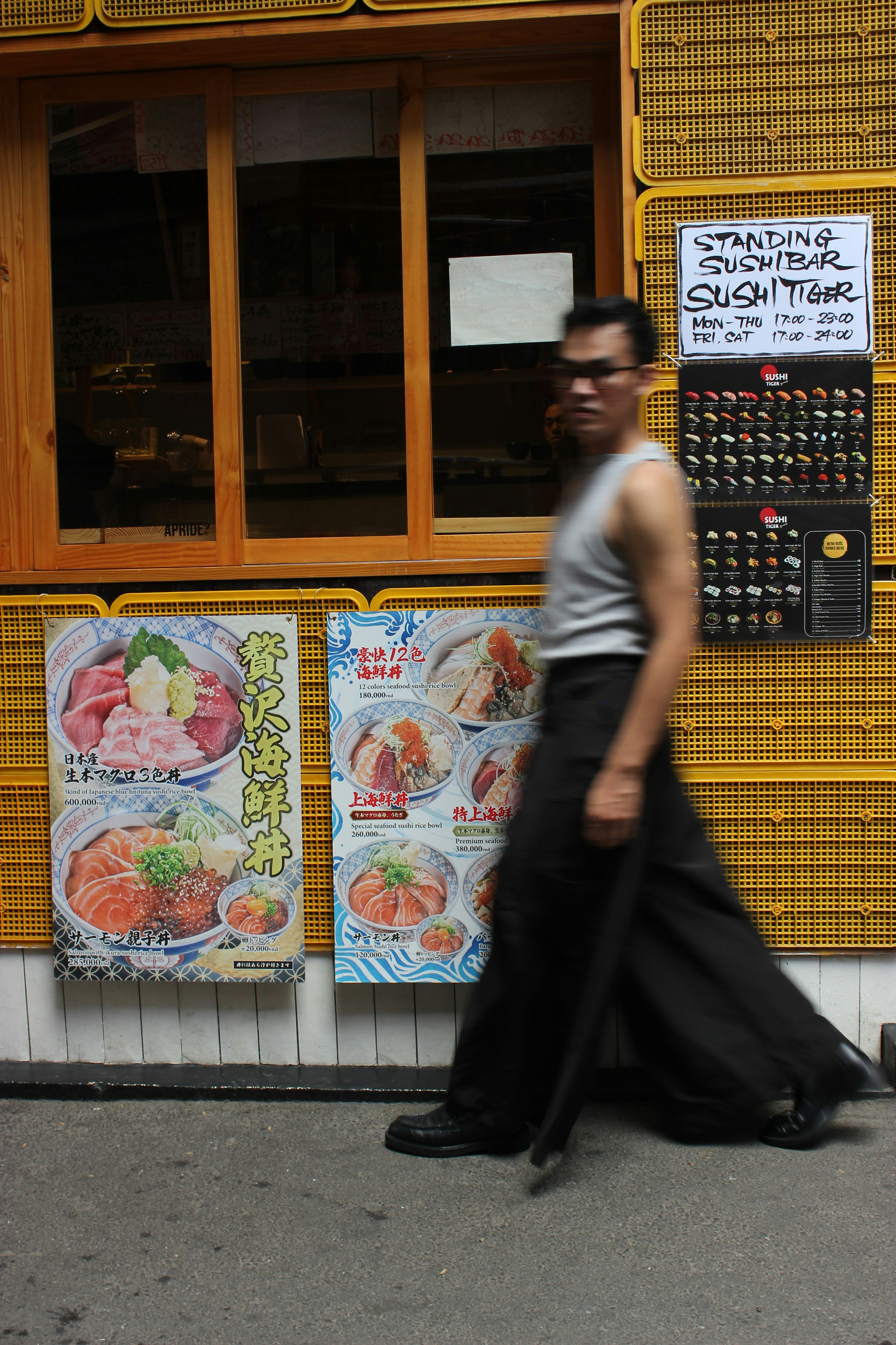 Midstride Figure in Front of a Yellow Sushi-Menu Wall