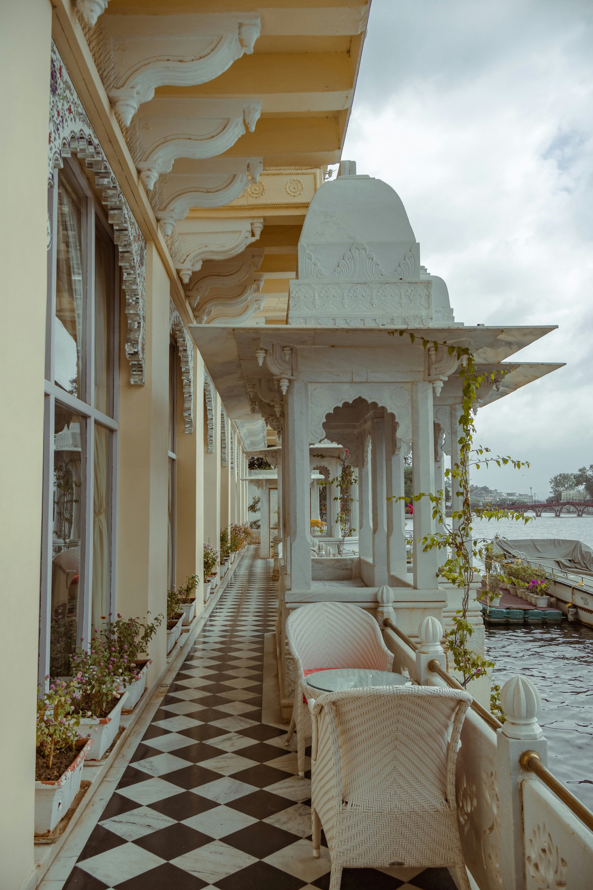 Capturing the timeless beauty of Udaipur, my photos showcase the enchanting shores of Lake Pichola and its surrounding wonders. | a couple of white chairs sitting on top of a black and white checkered floor