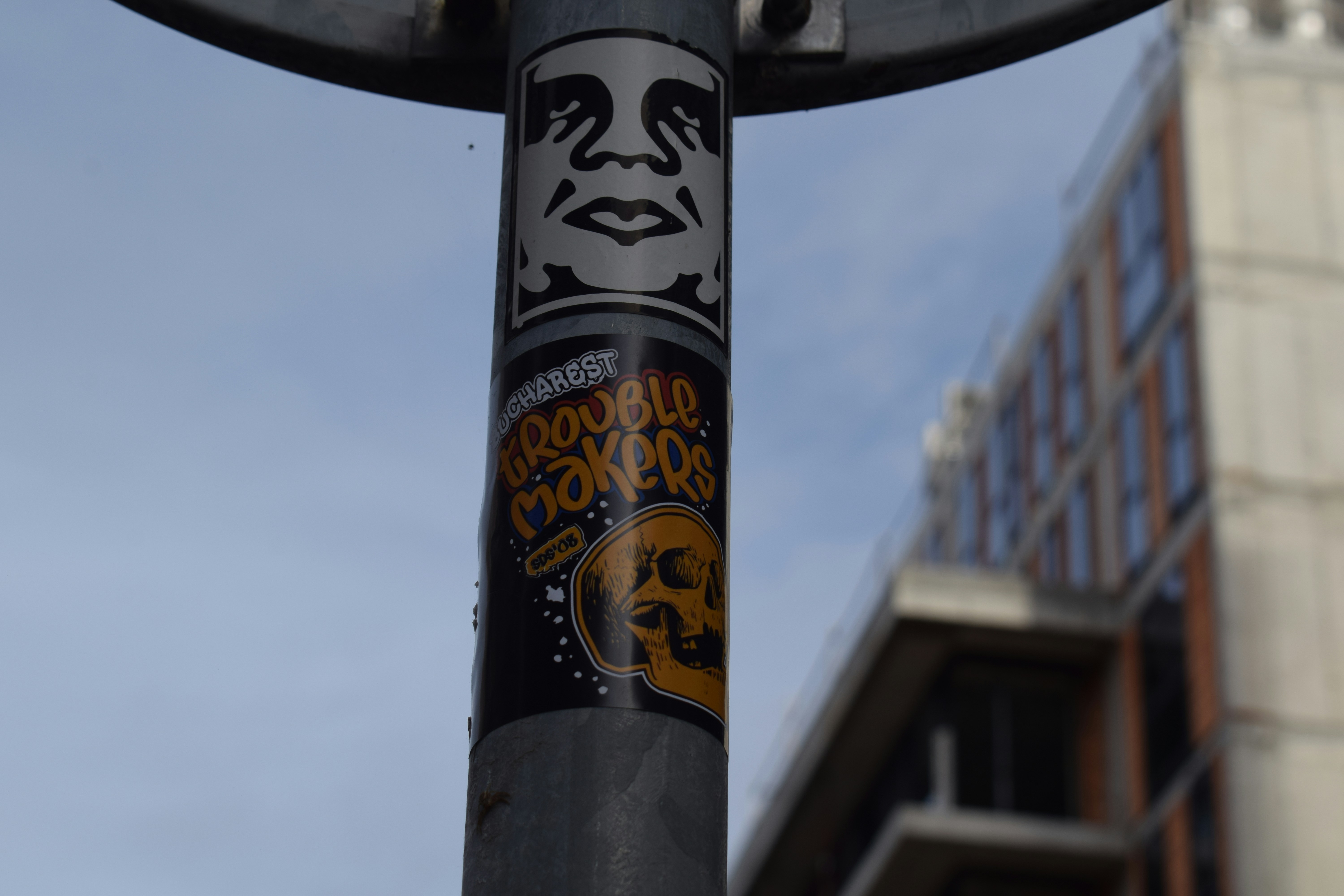 Cosmic Sticker on a Street Pole Framed by Sky and Construction