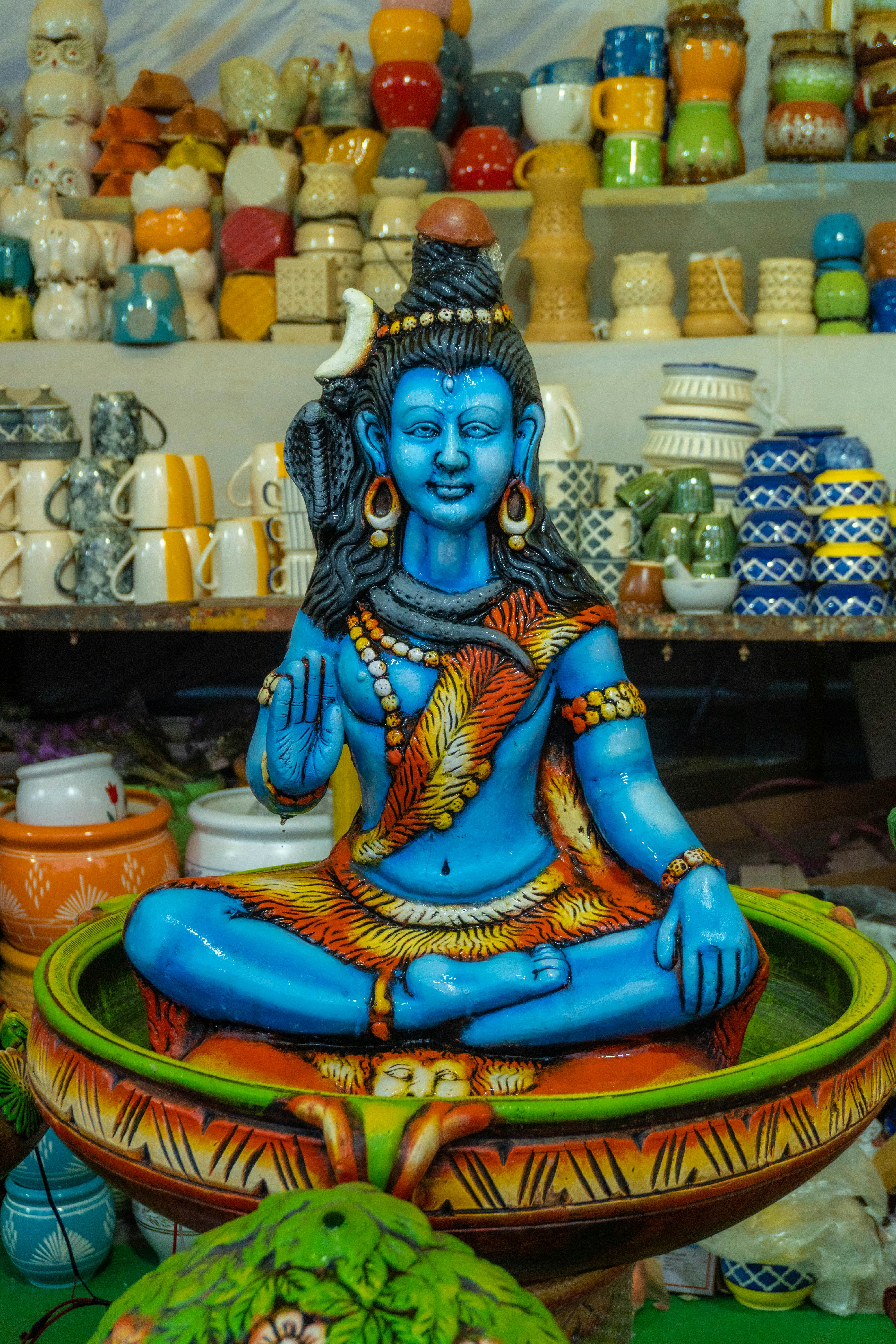 Azure Buddha Amid a Palette: Blue Statue in a Bustling Pottery Market