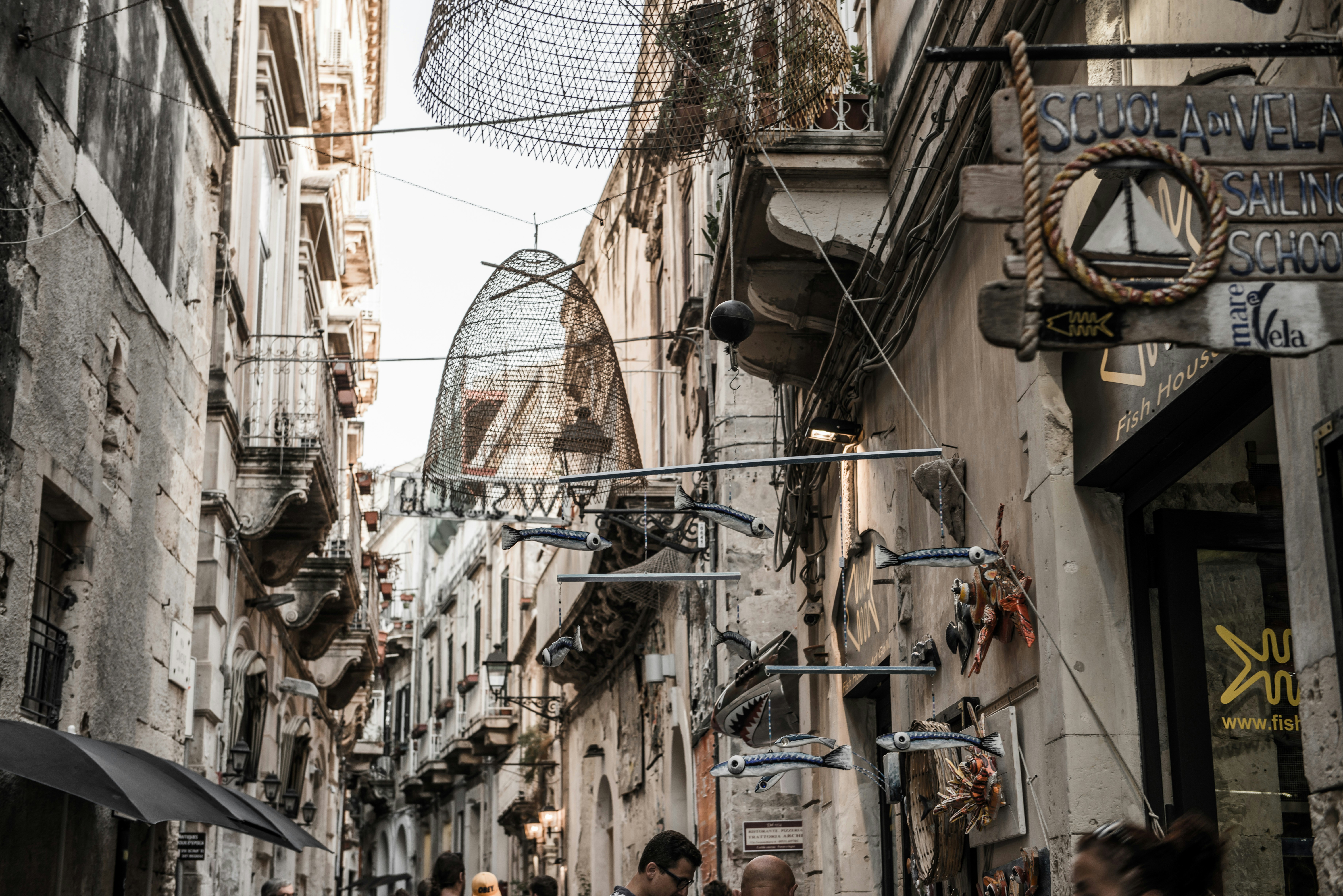 Narrow street lined with historic buildings and hanging art installations.