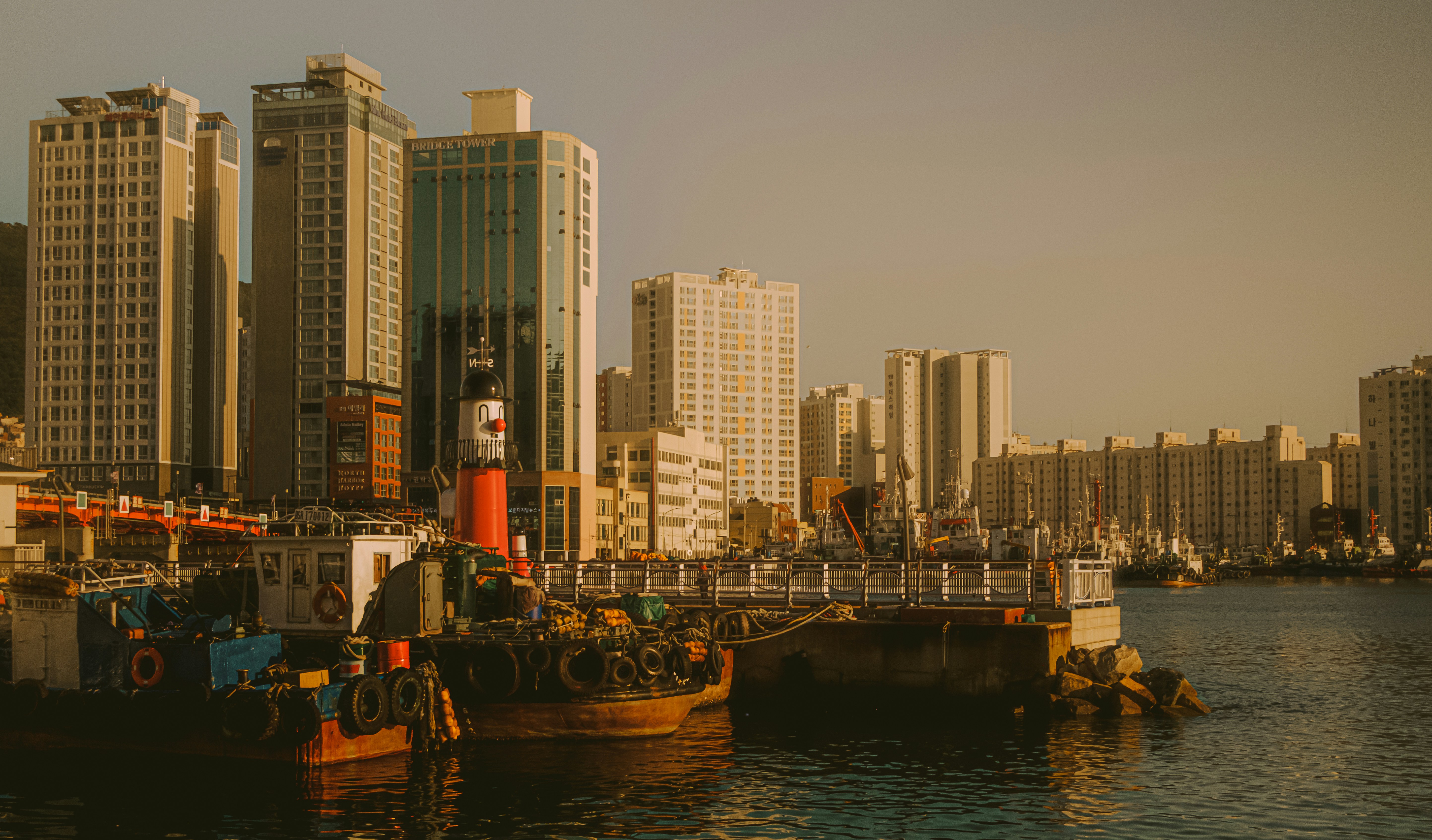 Harbor Beacon: Red Lighthouse Framing a Golden Cityscape