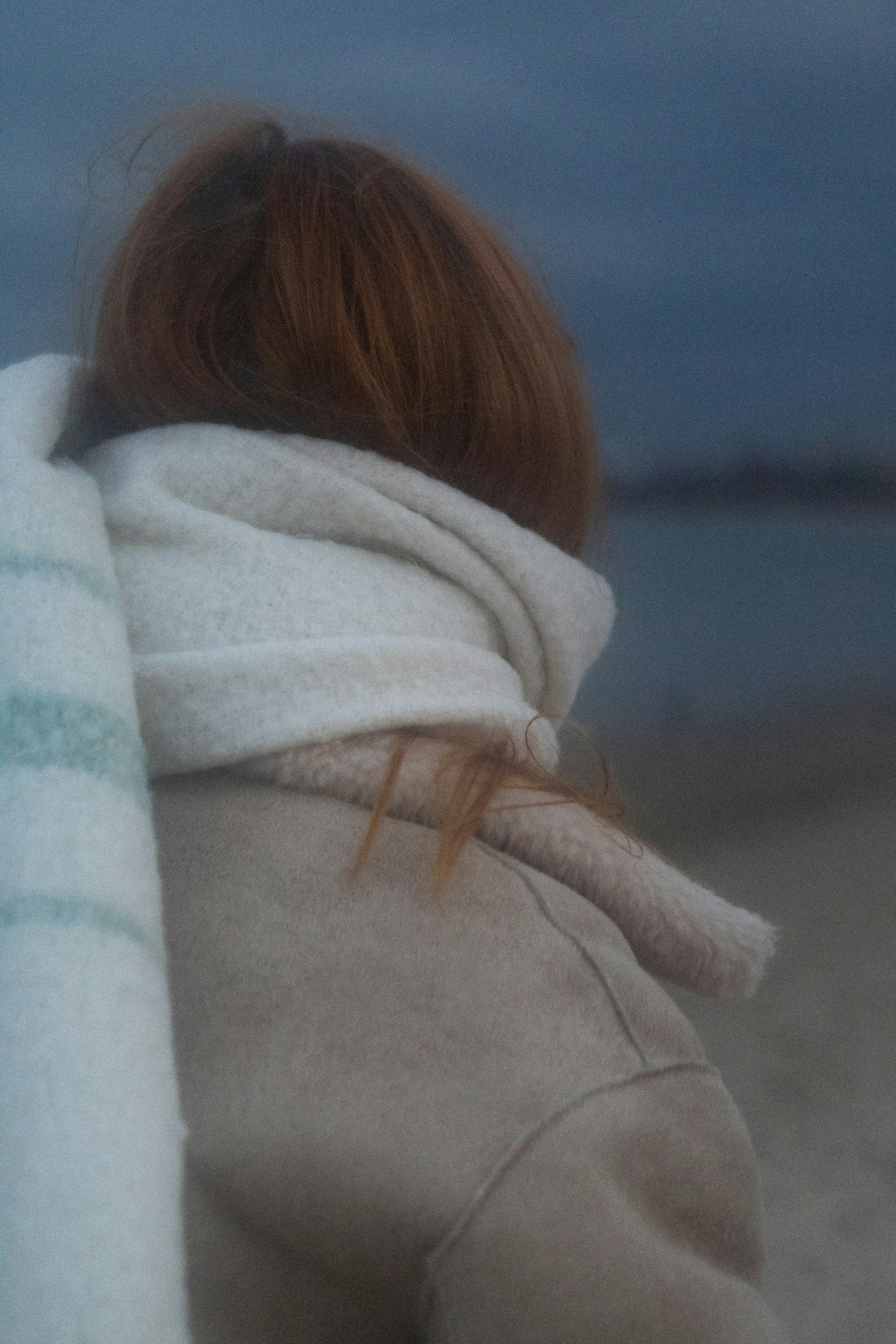Blue Hour by the Shore: A Wrapped Figure Against a Quiet Sea