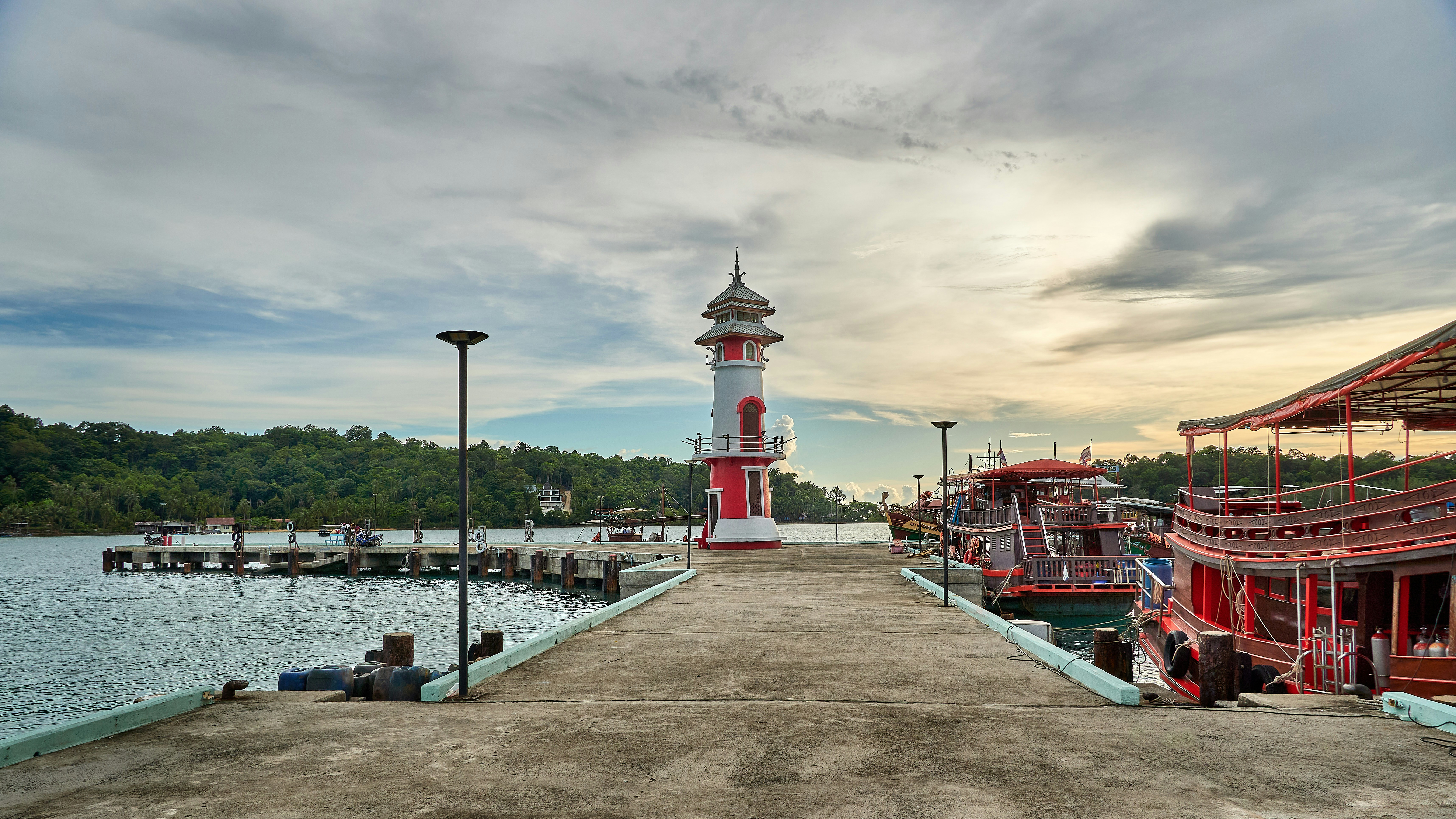 Foto Un faro rojo y blanco sentado en lo alto de un muelle – Imagen ...