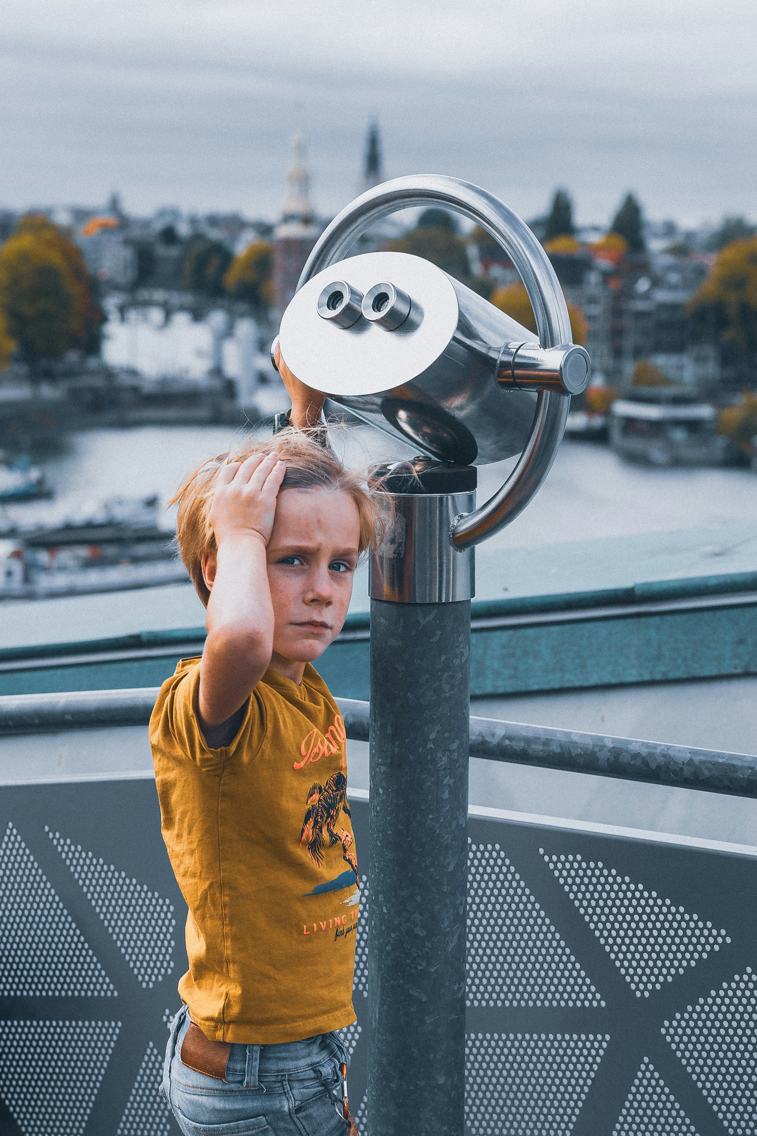 Child at a city overlook peering into a coin-operated viewfinder