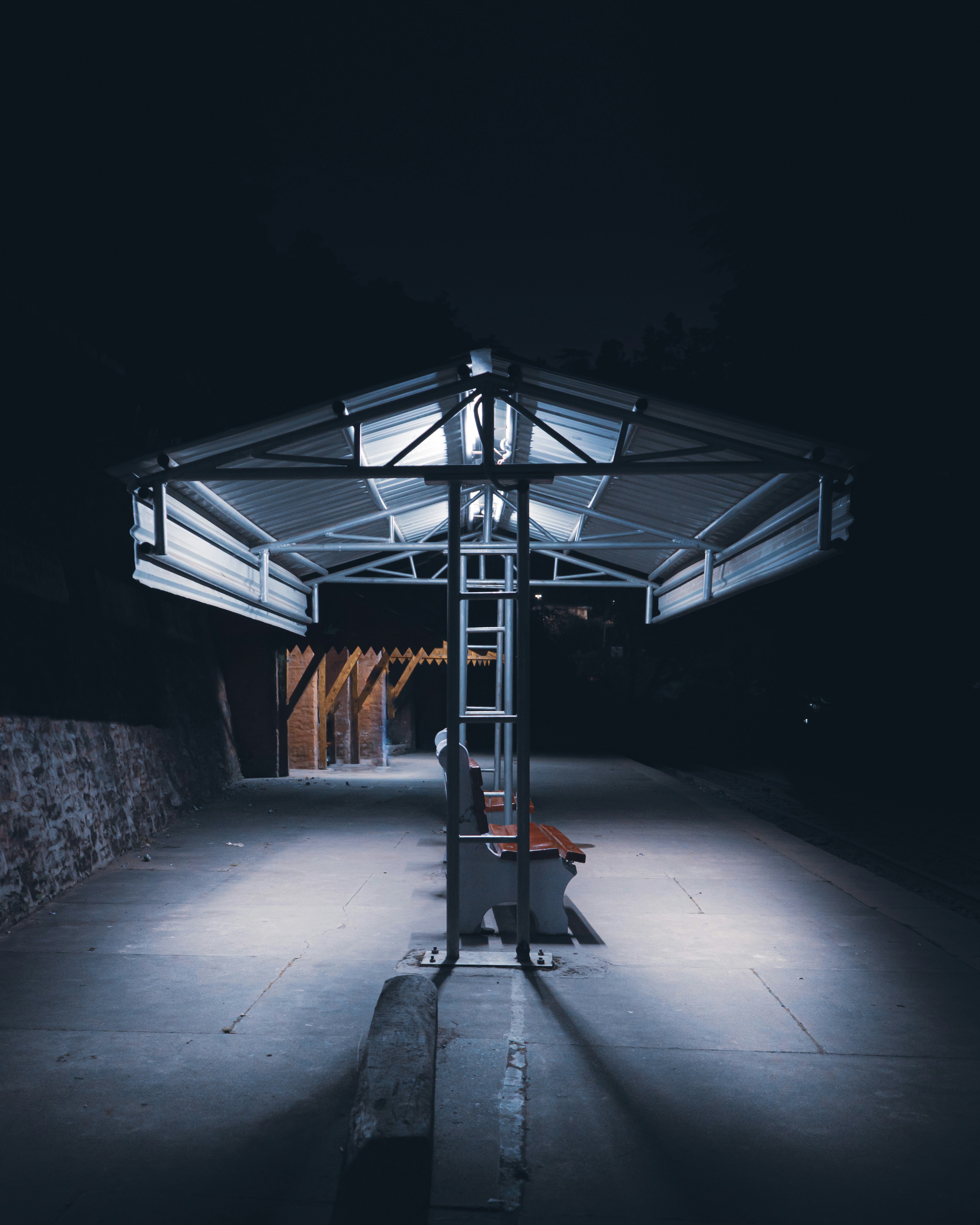 Night under the Steel Canopy: a cobalt-lit walkway framed by a triangular lattice