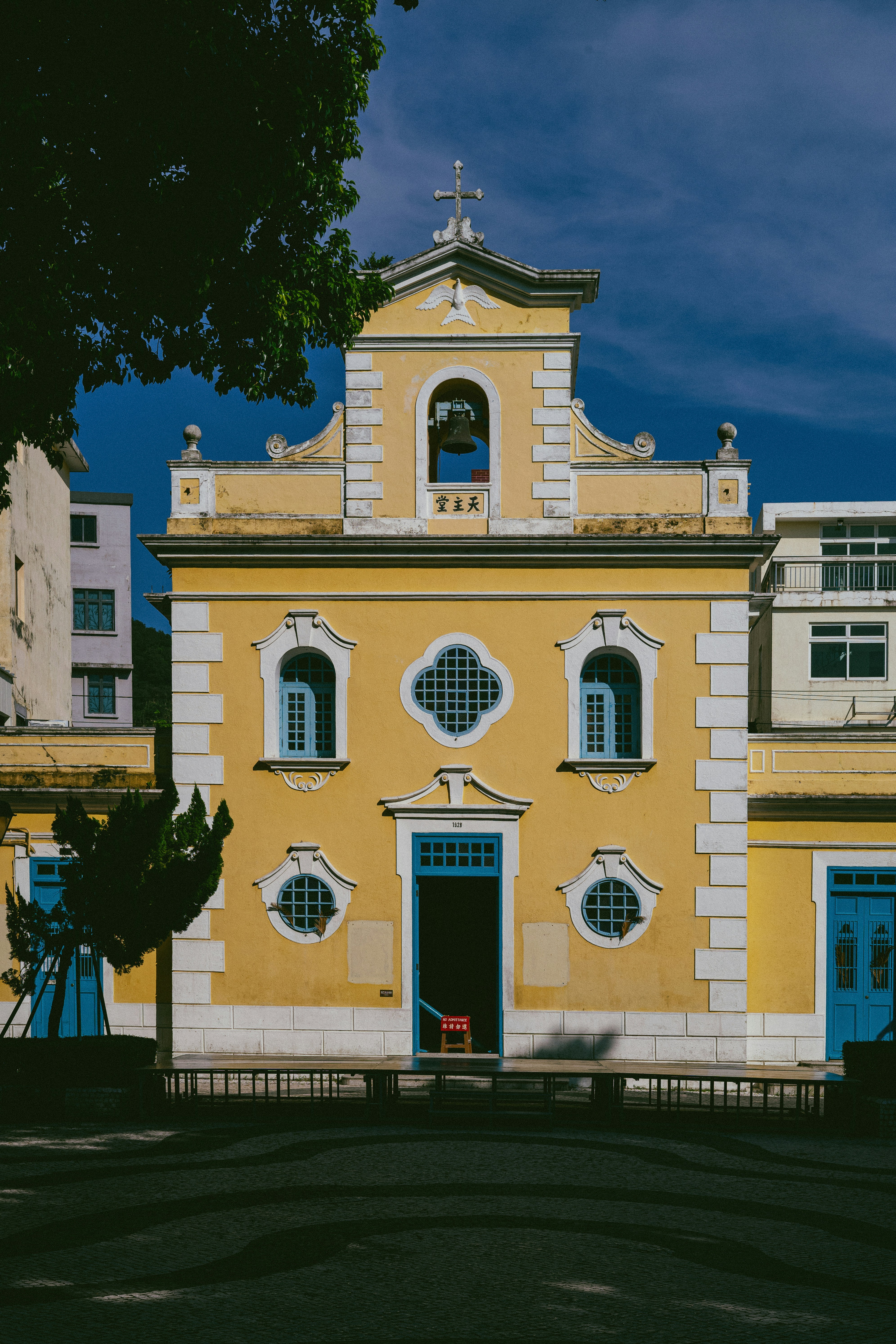 Sunlit Yellow Chapel Facade Framed by Bright Blue Doors