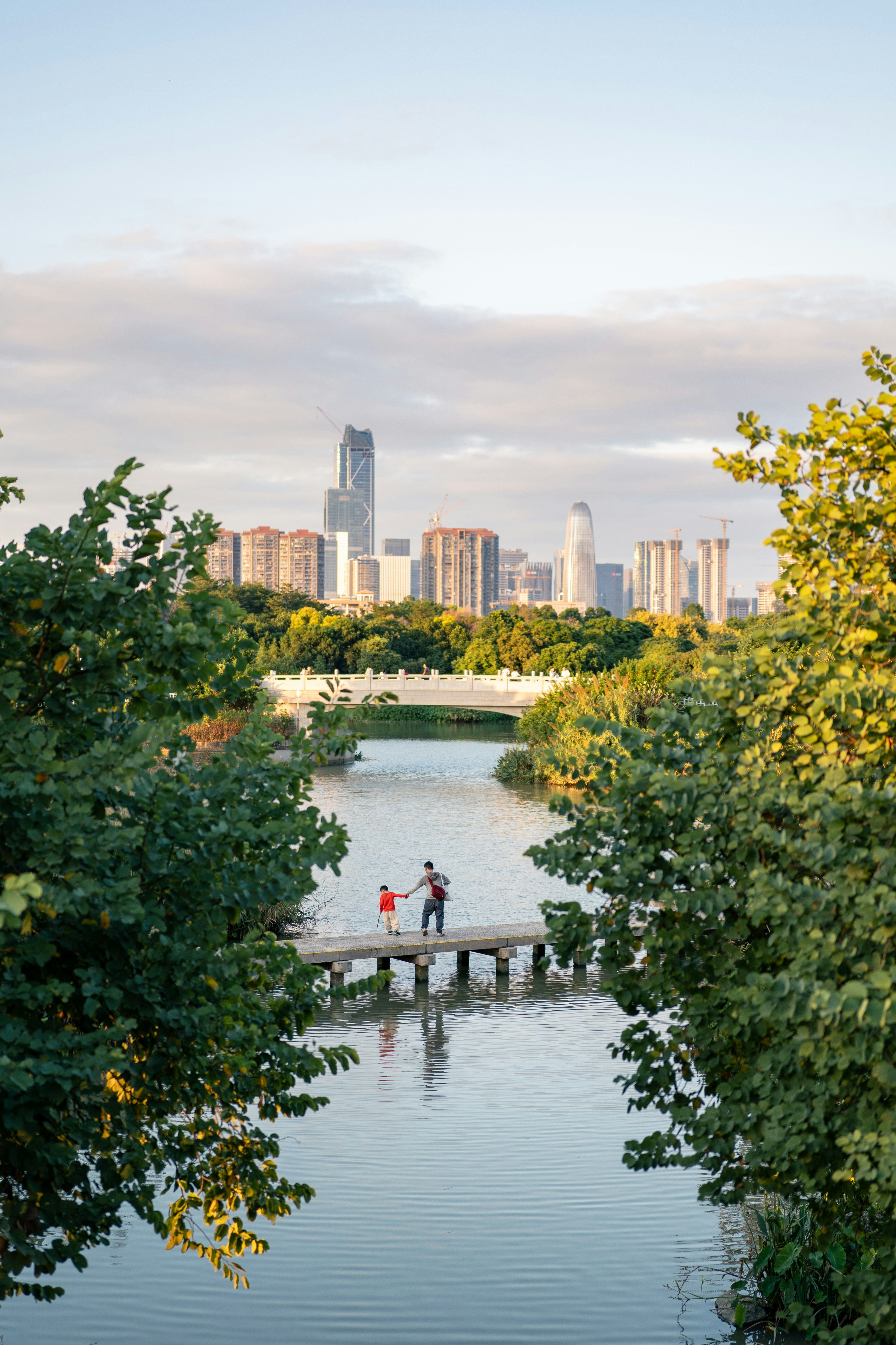 Pedestrian Bridge over a Quiet River with City Skyline