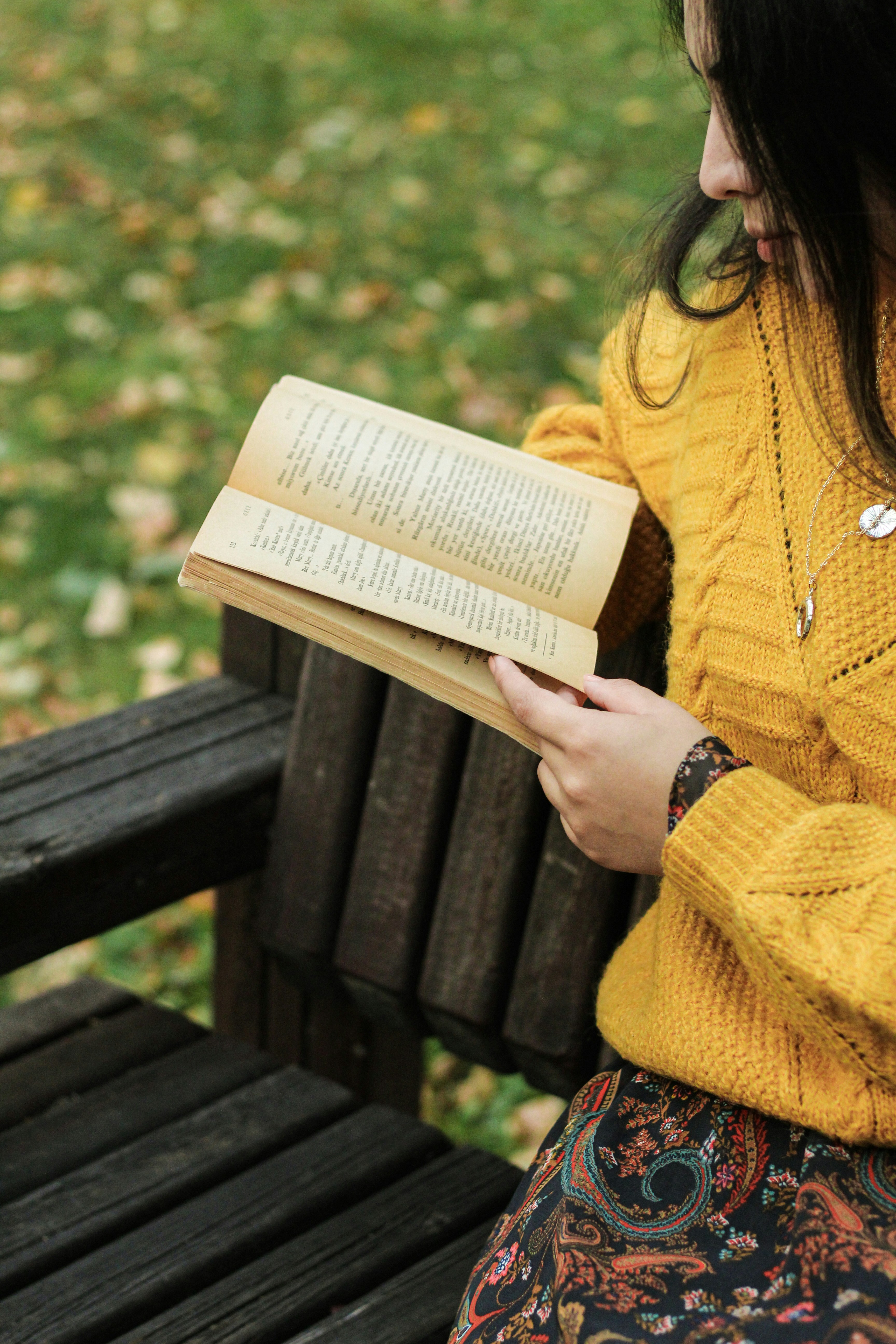 A woman sitting on a bench reading a book photo – Free Image on Unsplash