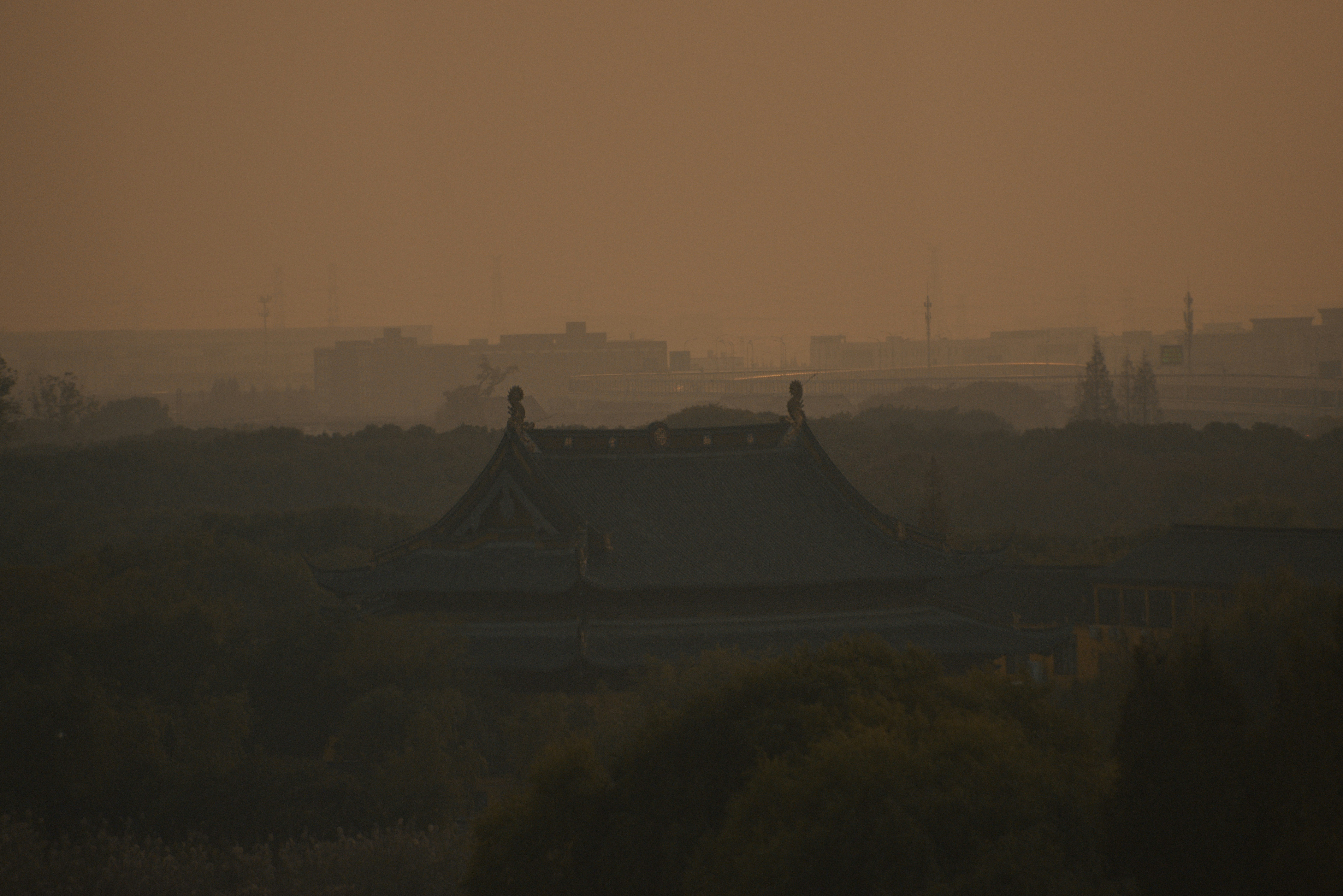 Temple Silhouette in Rust-Haze Over a Quiet Suburban Skyline