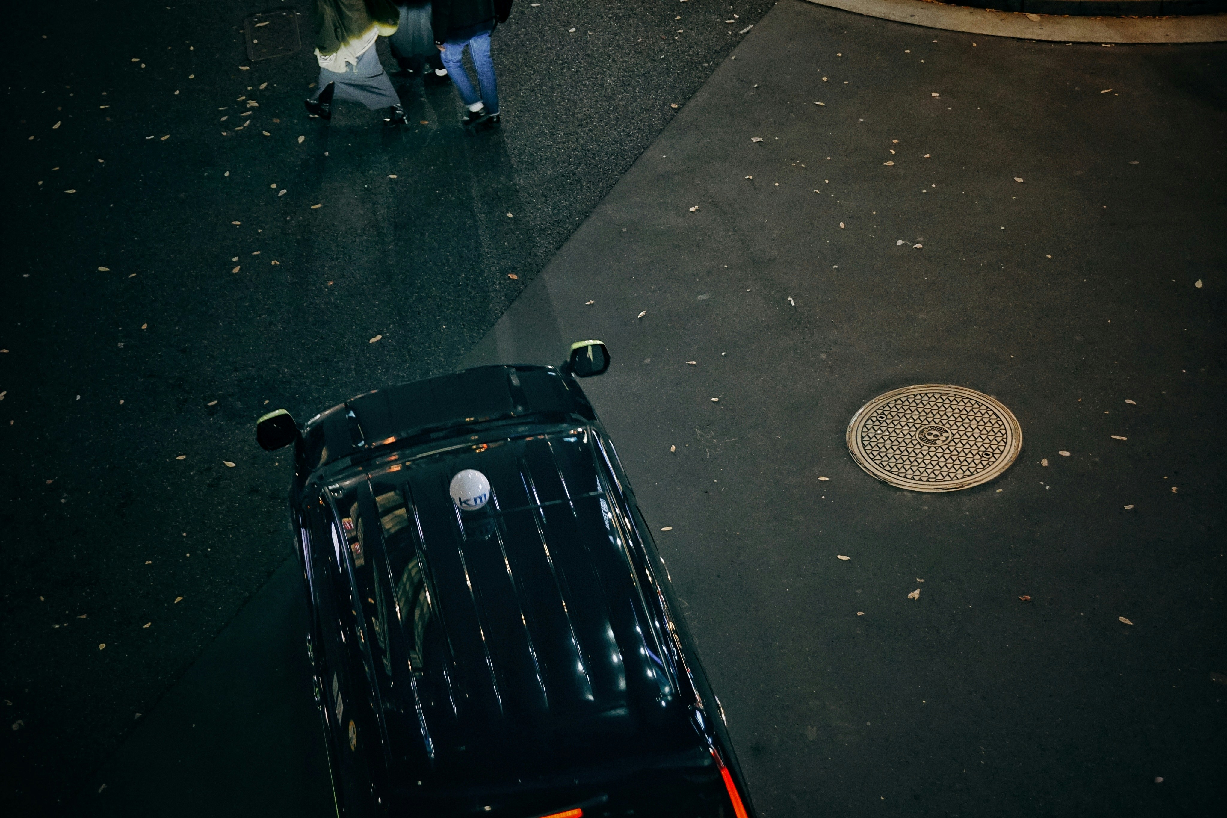A car parked on the side of a road next to a manhole photo – Free Grey ...