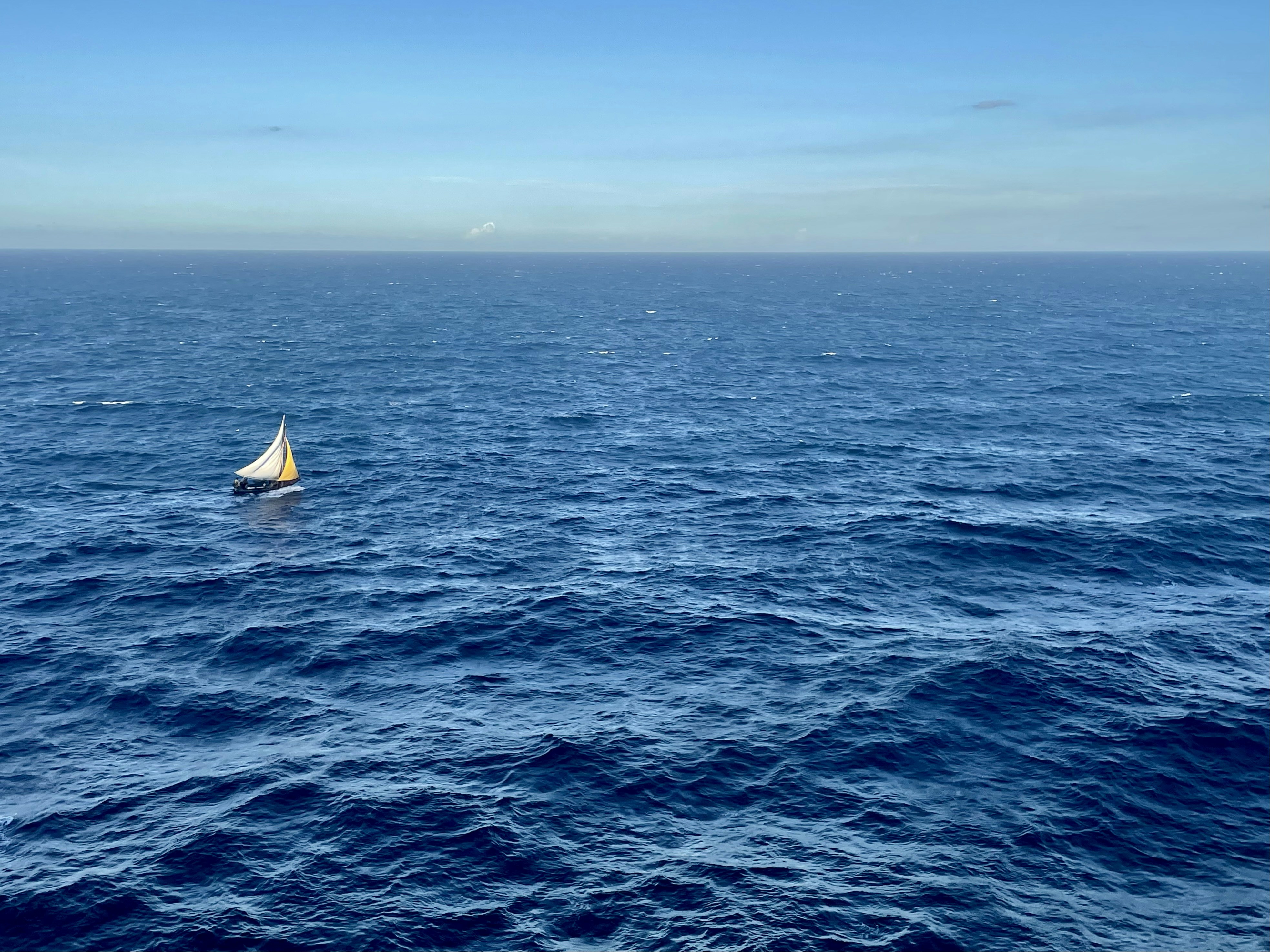 Lone Sail Across a Vast Indigo Ocean
