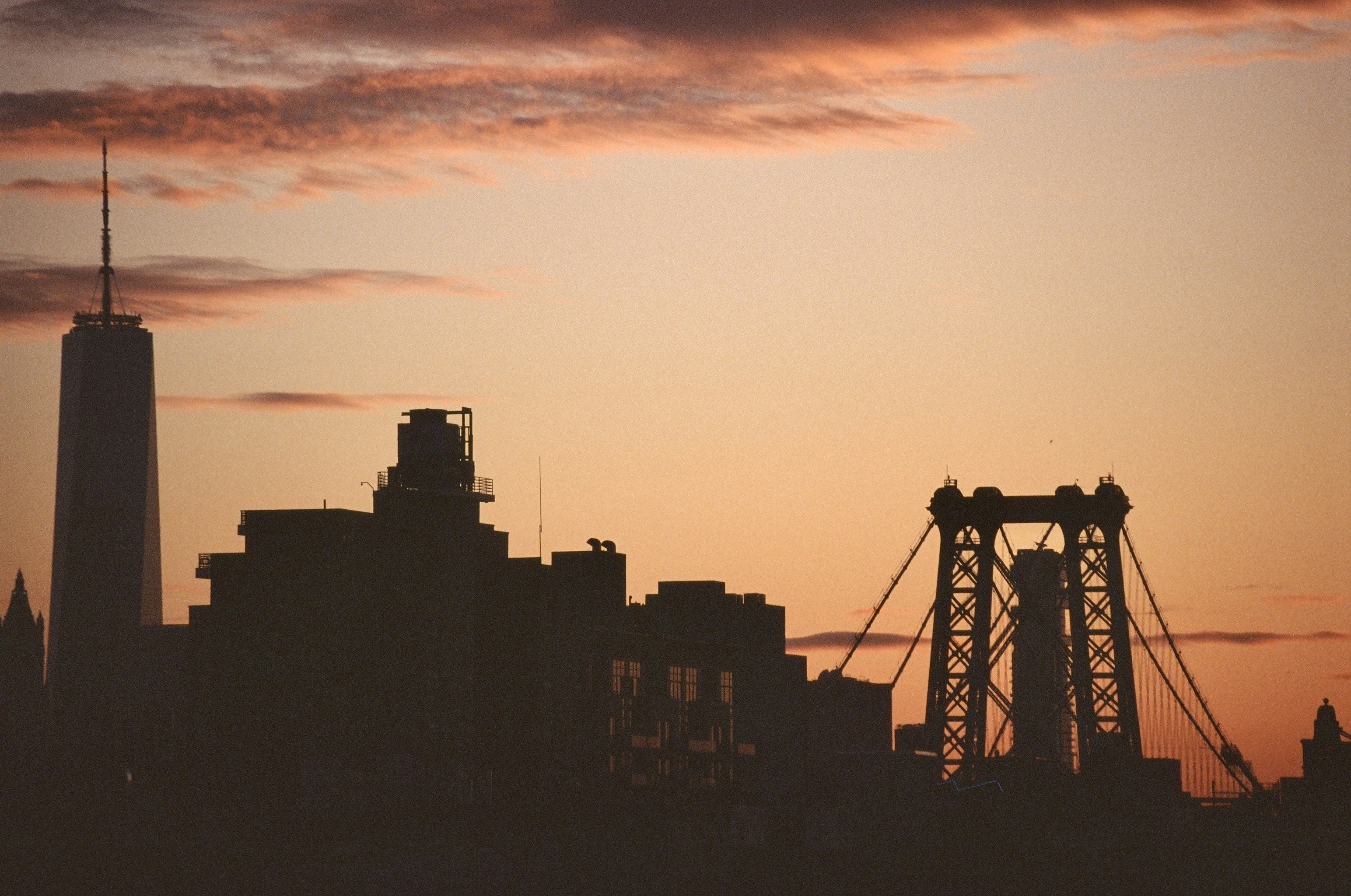 Silhouetted skyline and bridge against a vibrant sunset sky.