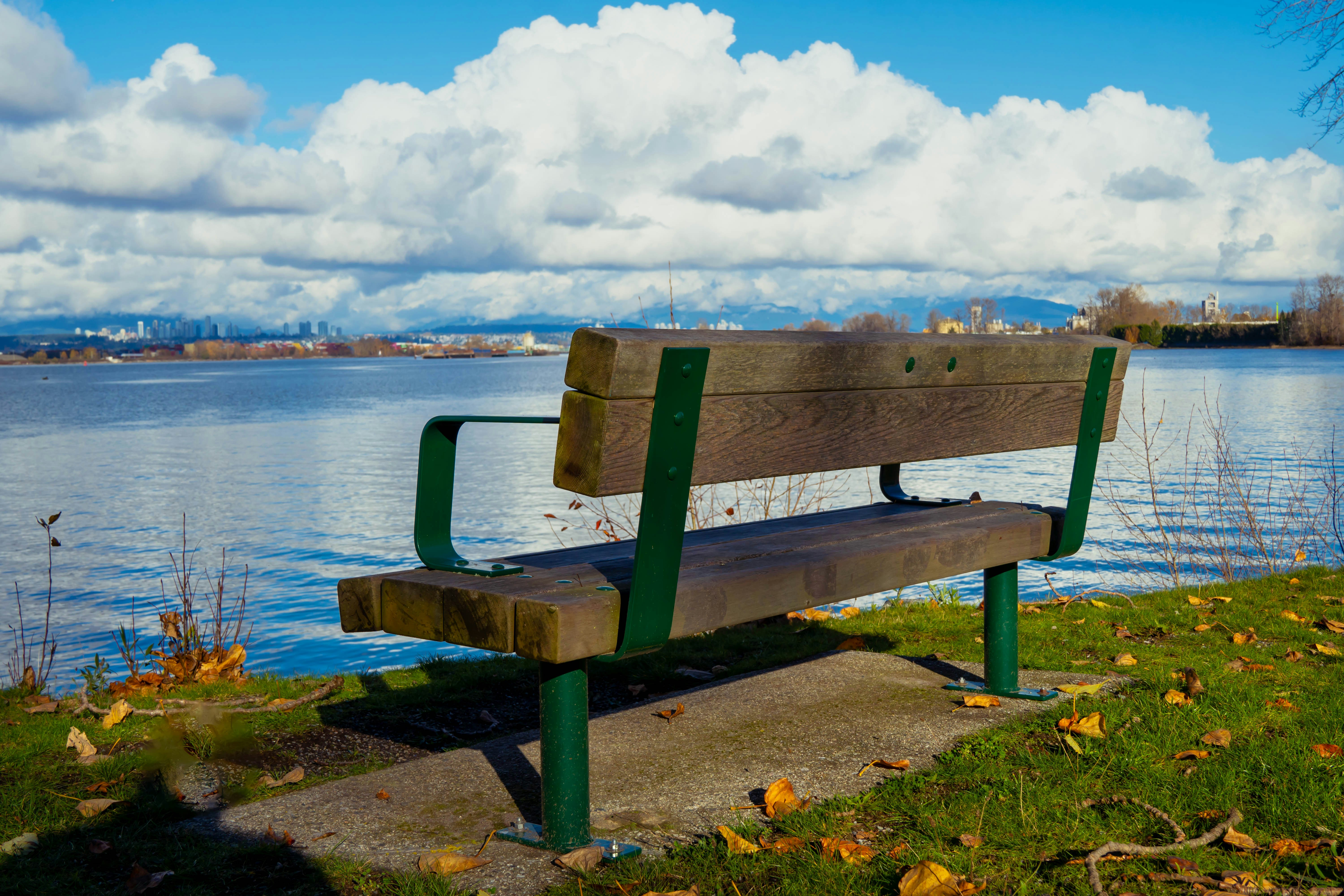 Weathered Riverside Bench Overlooking a Lake Under a Cloud-Filled Sky