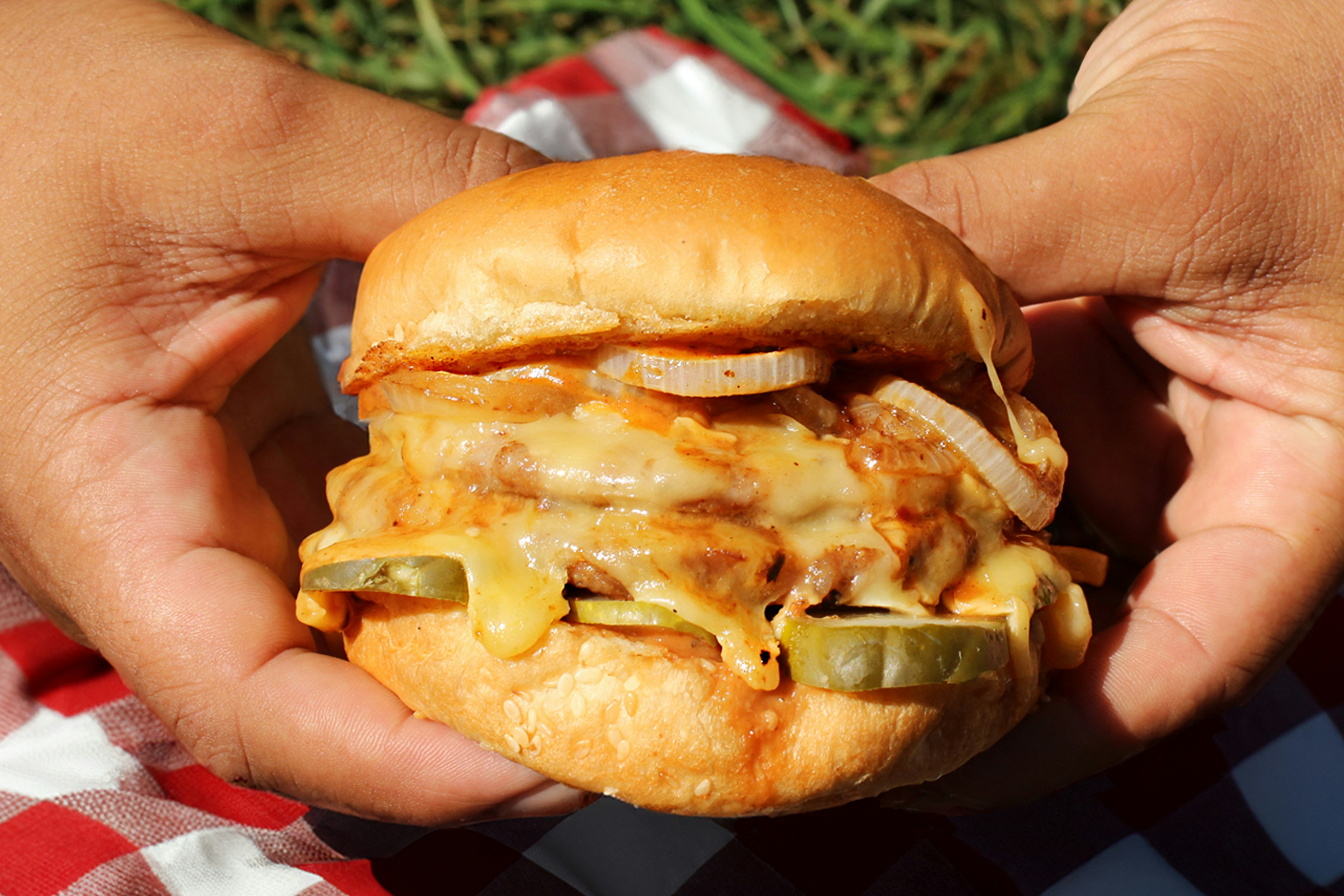A person holding a cheeseburger in their hands photo – Free Food Image ...
