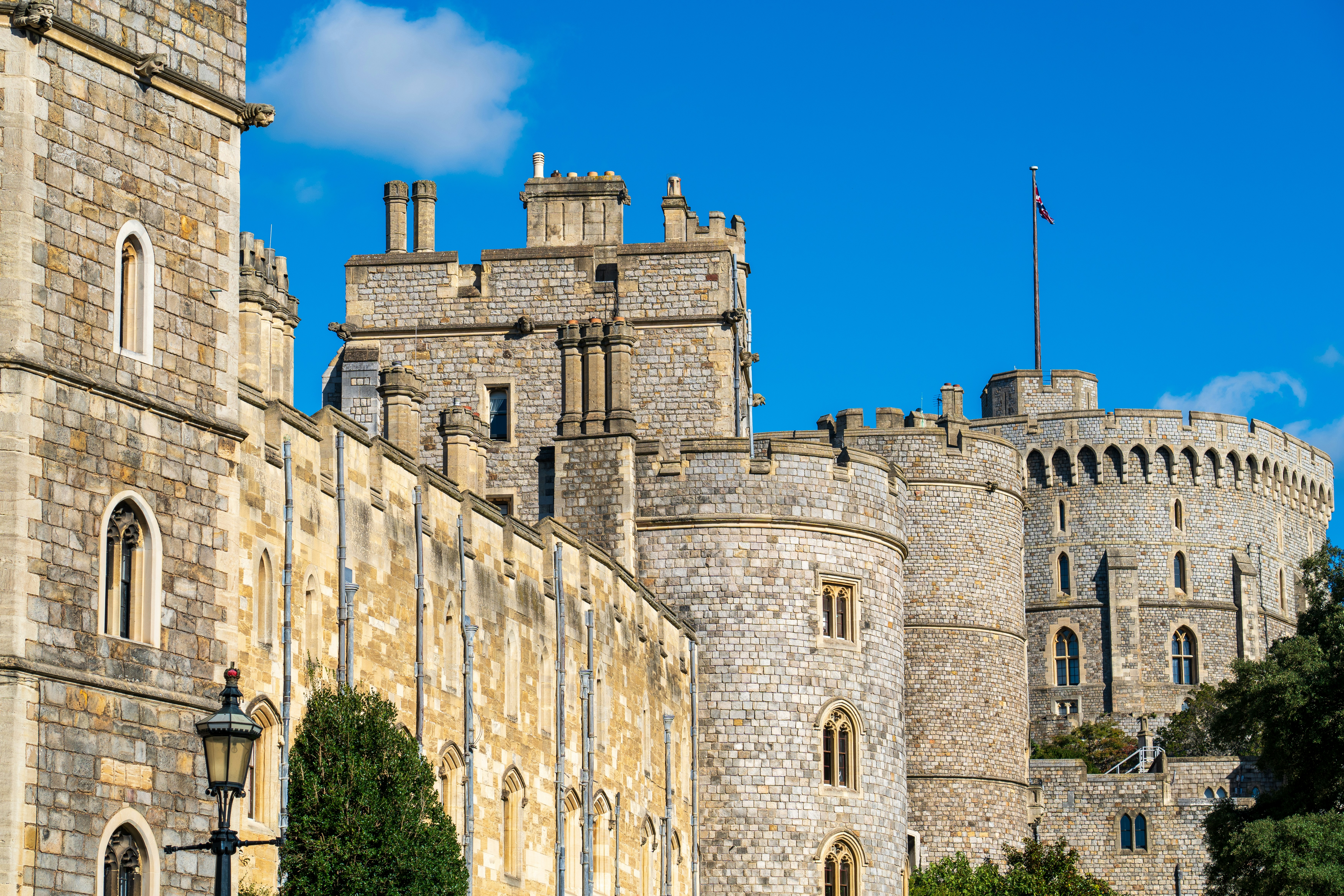 Historic stone castle with a prominent clock tower under a clear blue sky.