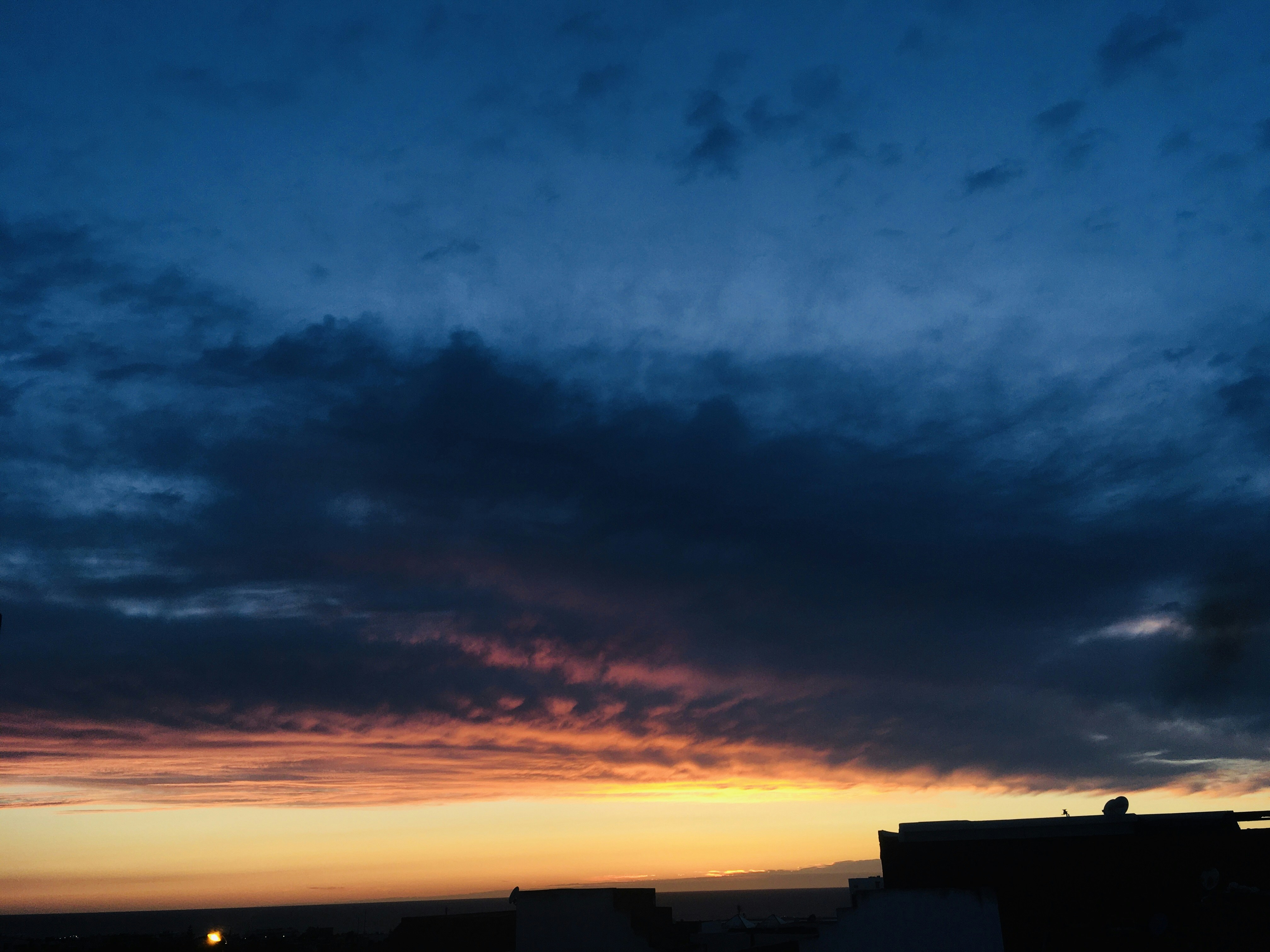Vibrant sunset sky with deep blues and warm oranges above silhouetted buildings.