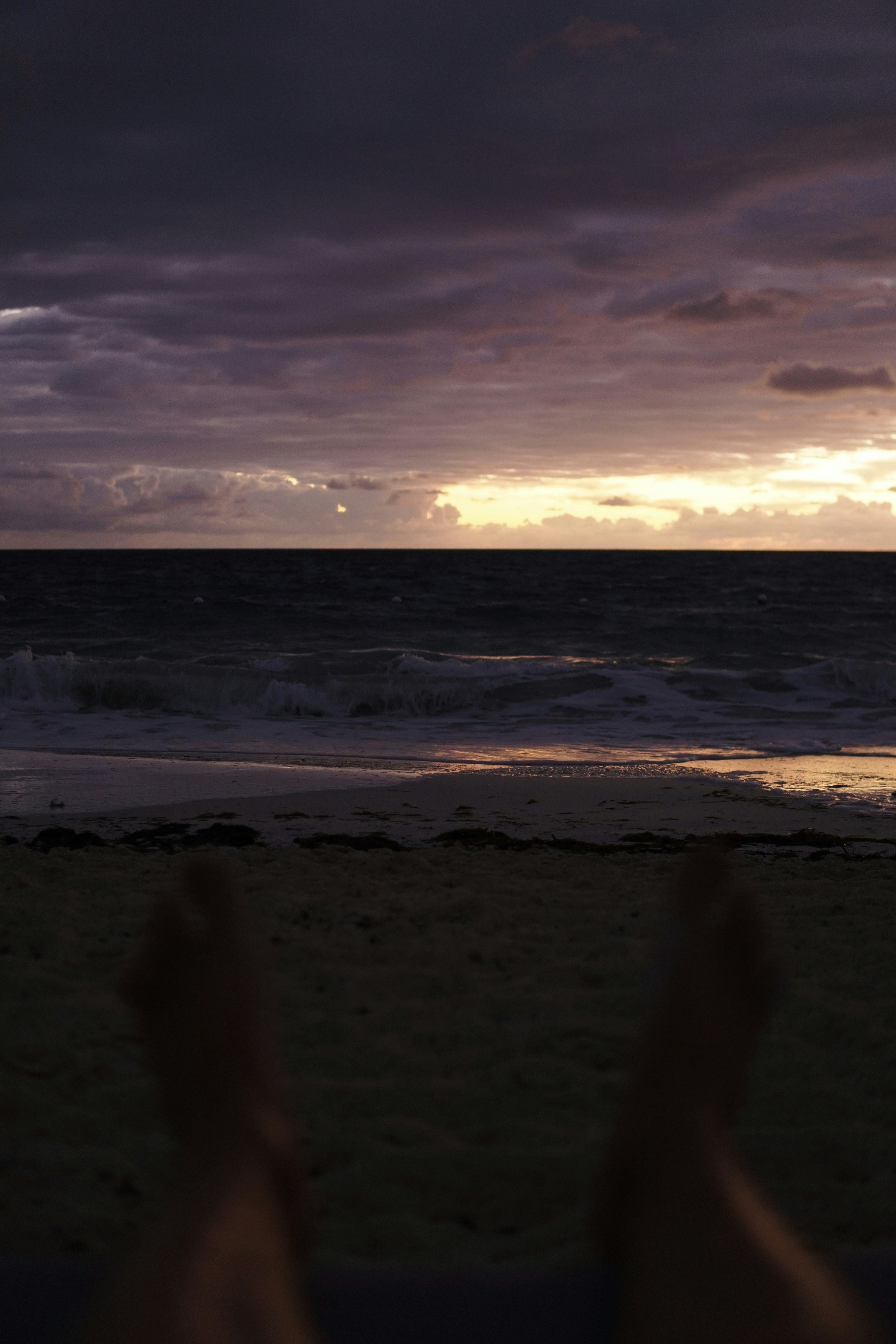 Dusk's Edge: Silhouetted Feet and the Glowing Horizon