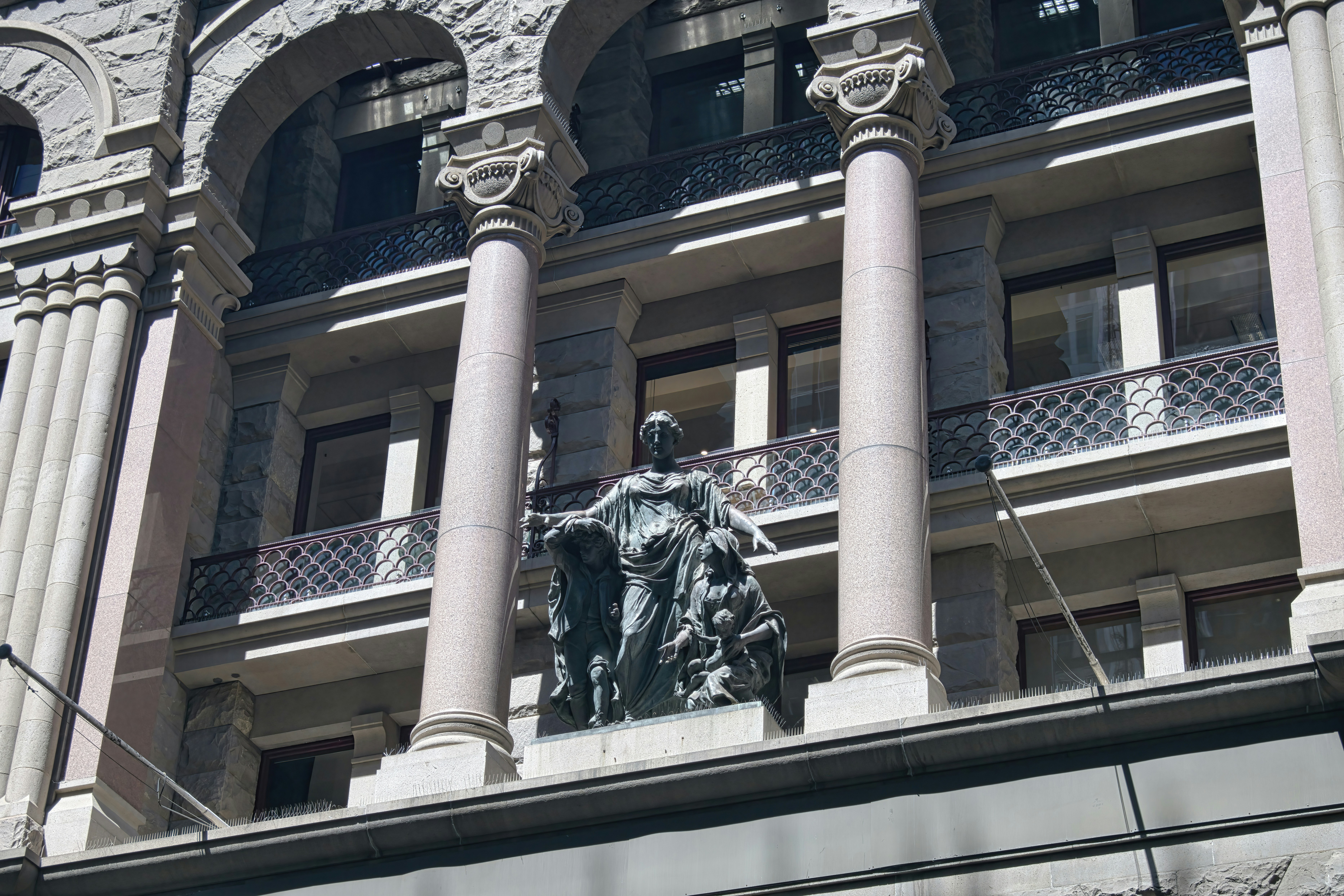 A majestic statue of a figure surrounded by columns on a historic building facade, symbolizing strength and protection.