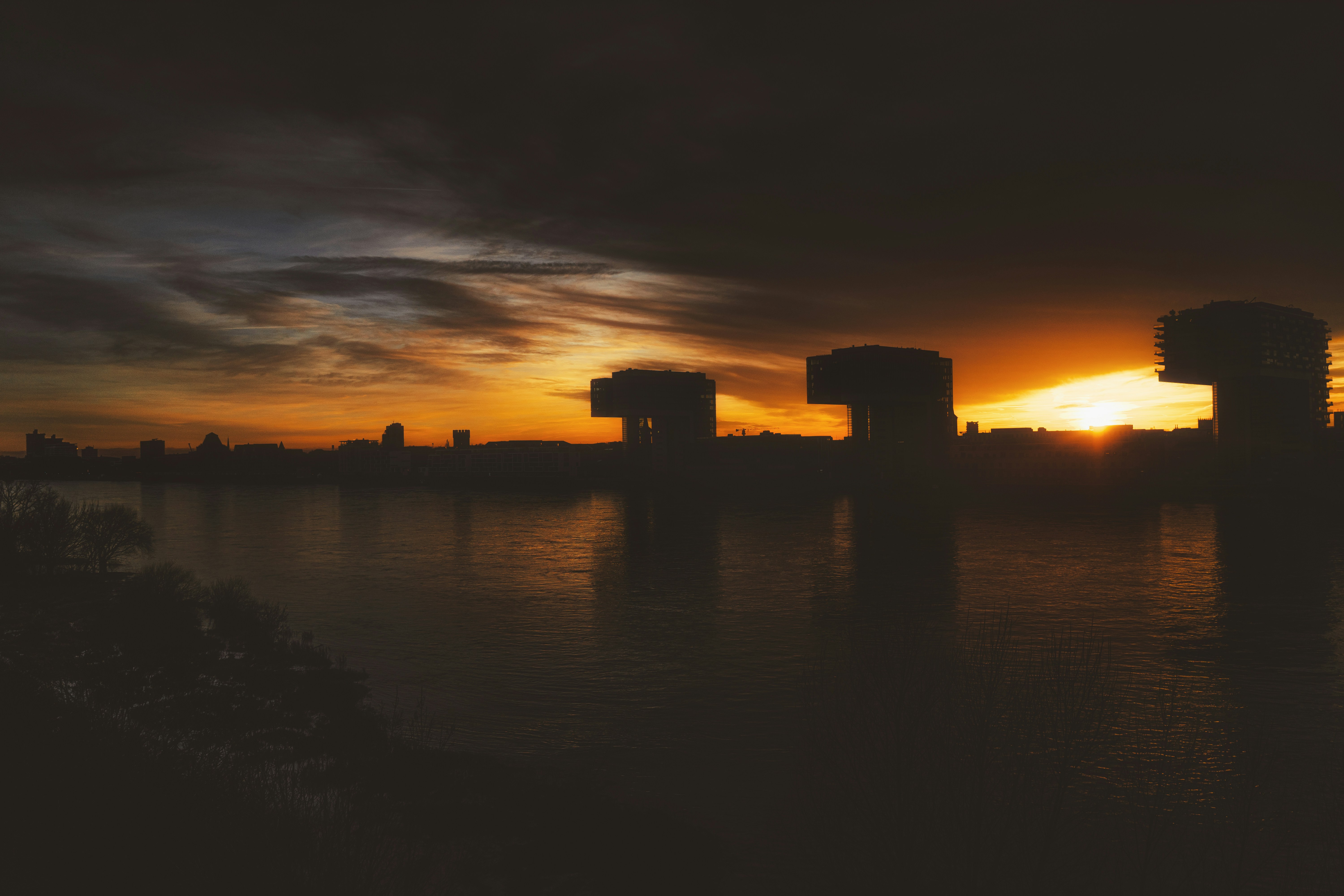 Silhouetted structures against a vibrant sunset sky over calm water.