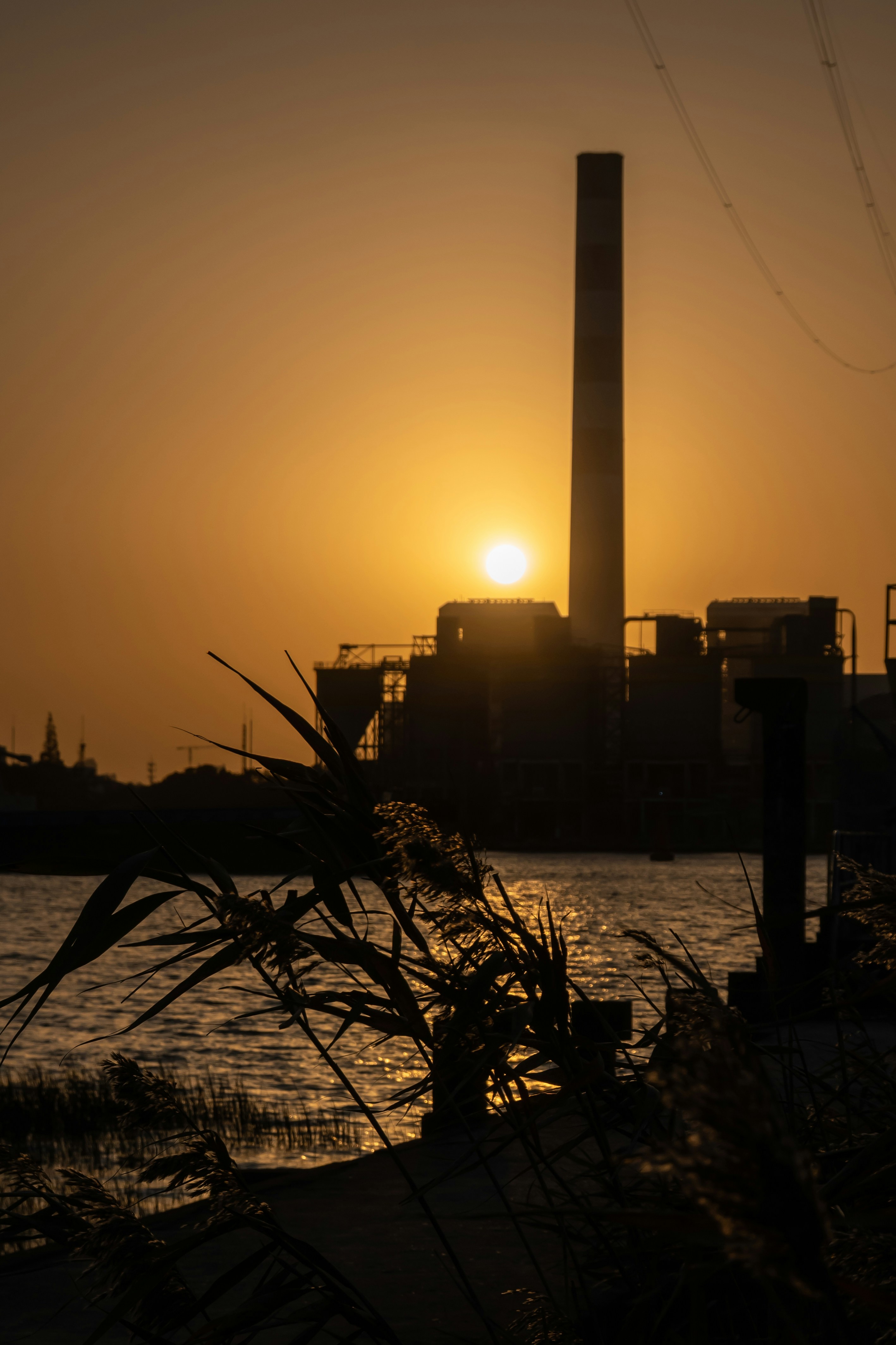 Golden Hour Over the Riverside: Silhouettes of Industry Against a Warm Horizon