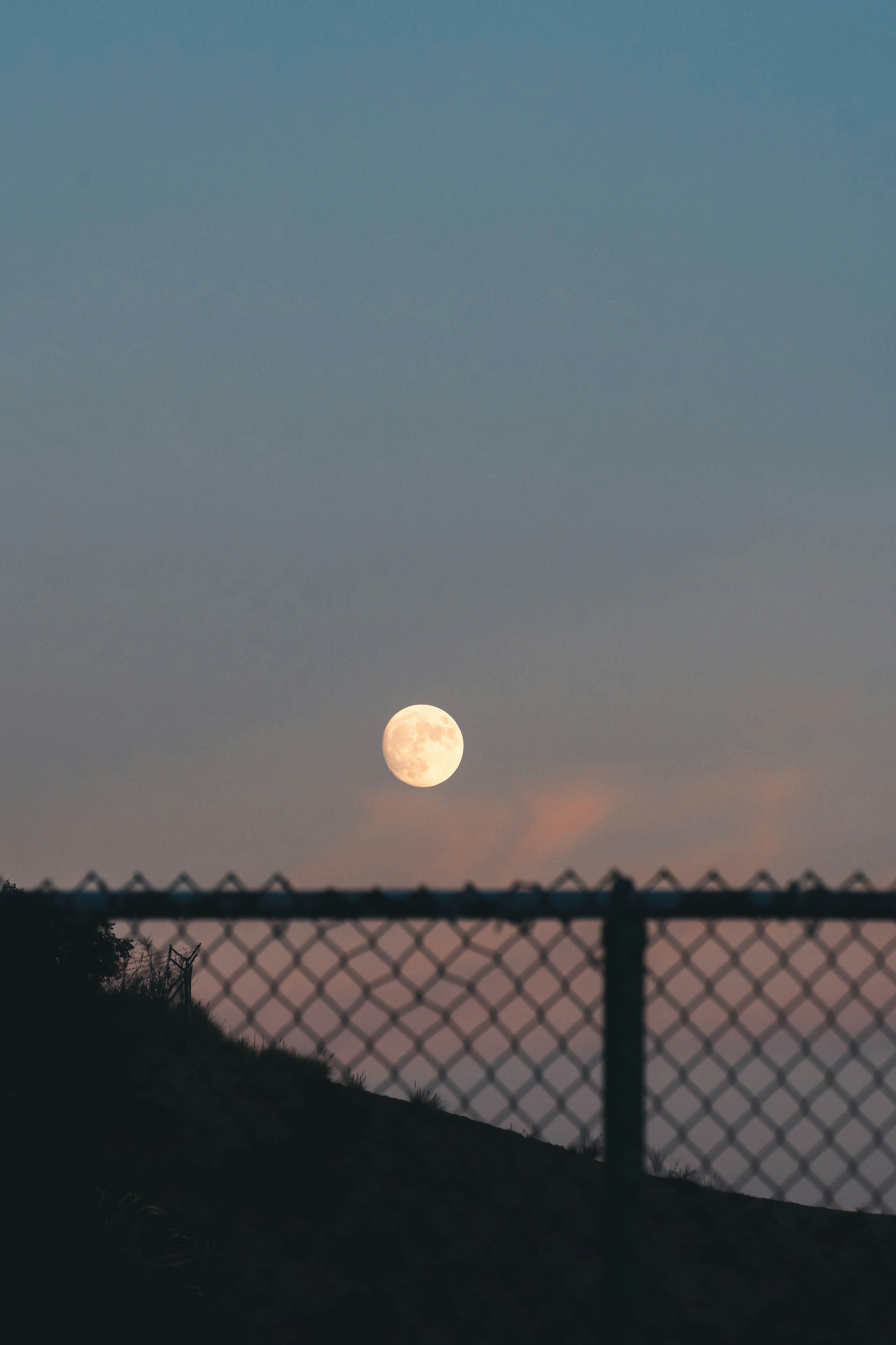 Moonrise over a Chain-Link Horizon